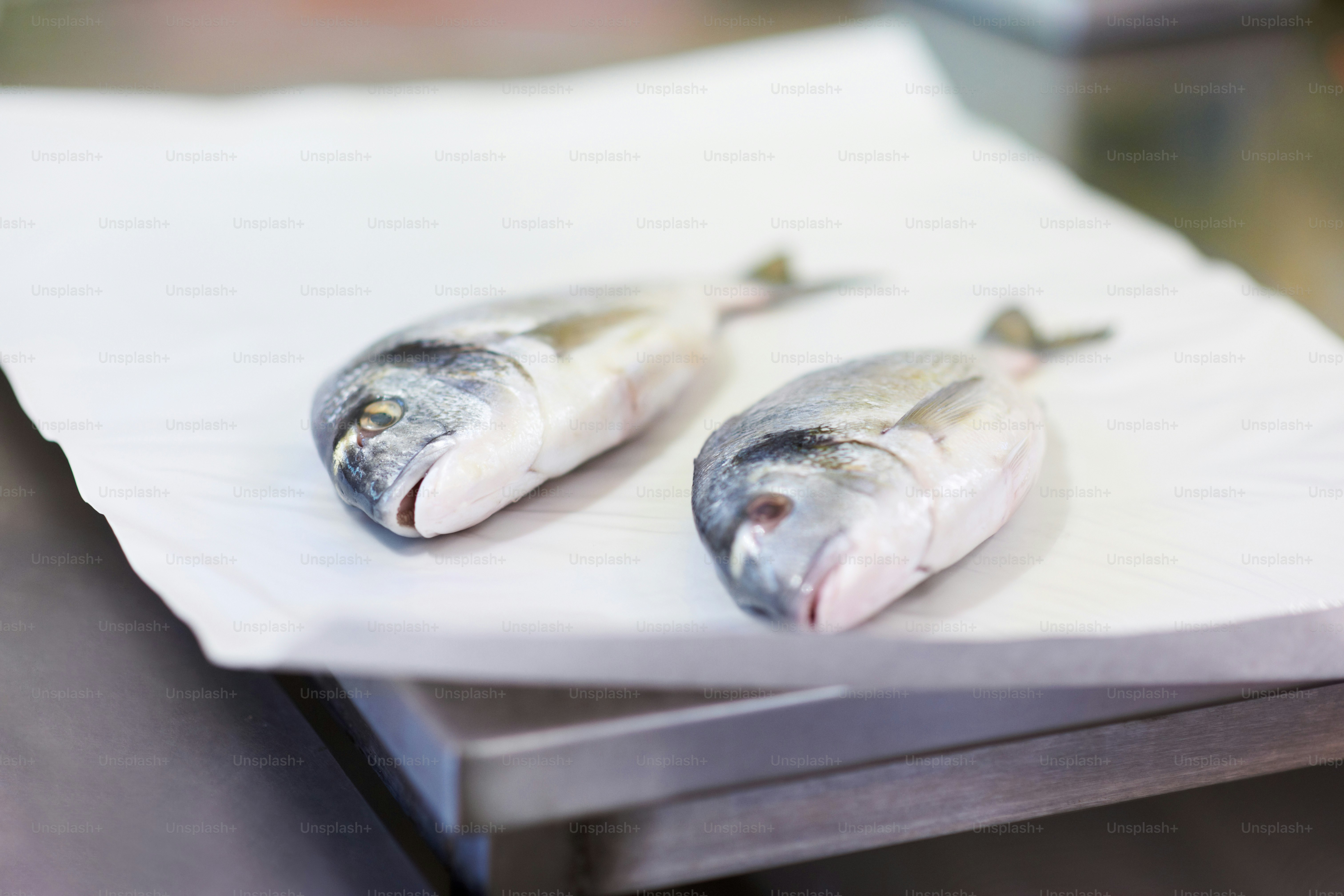 Zwei Fische, die auf einem weißen Papiertuch sitzen Foto – Bild zum ...