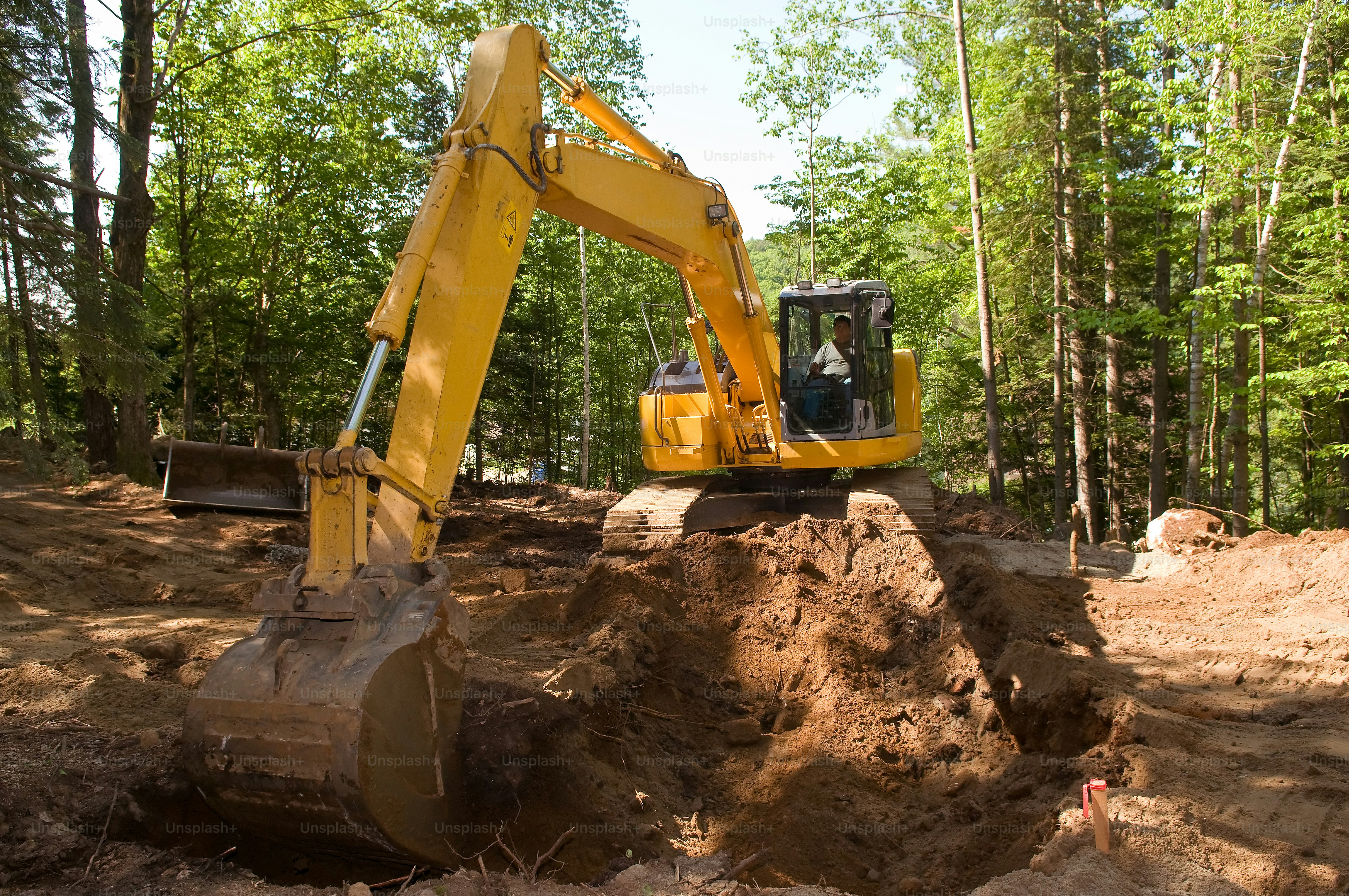 A yellow excavator sitting on top of a pile of dirt photo – Occupation ...