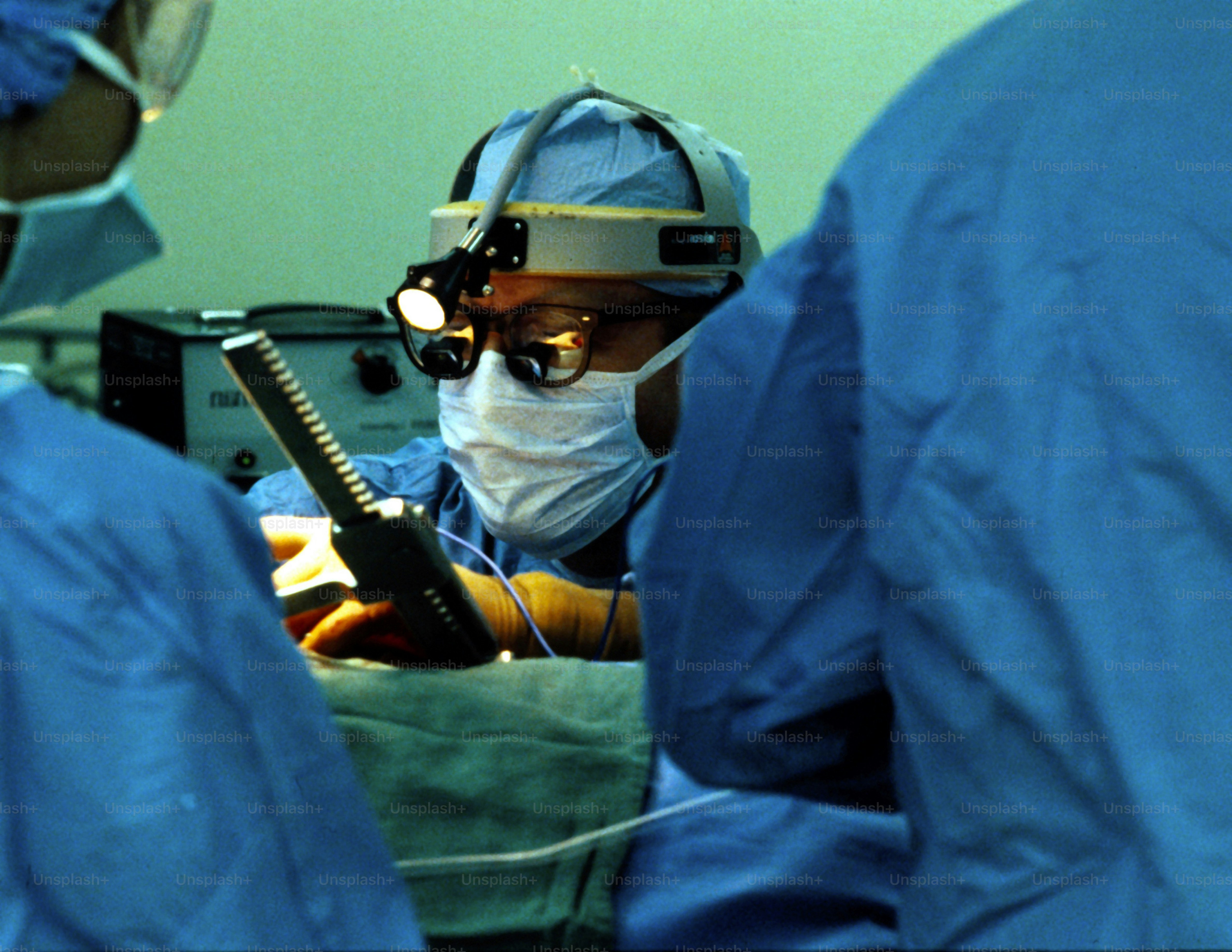 A group of doctors in scrubs operating on a patient photo – One person ...