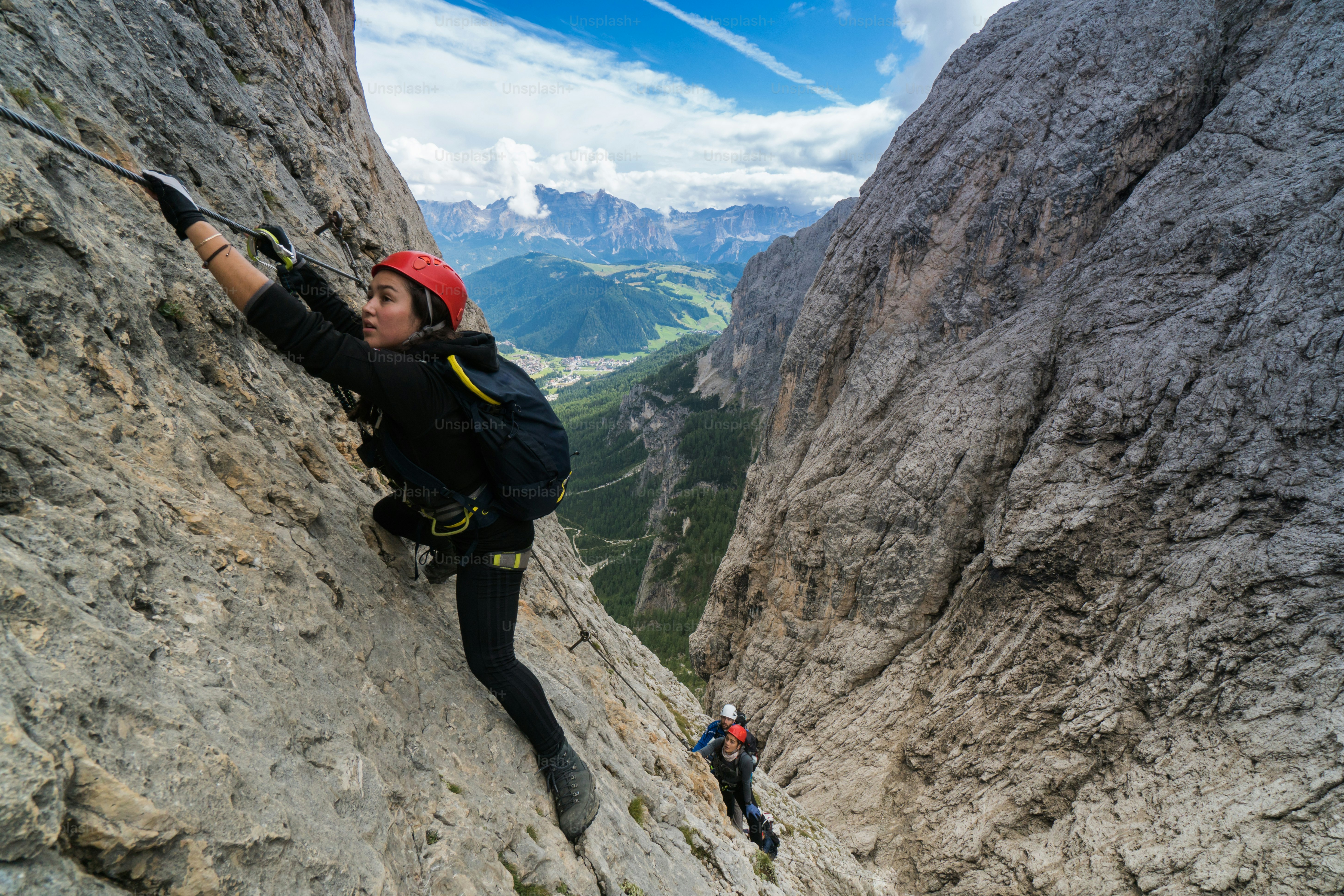 Three mountain climbers on a difficult Via Ferrata in the Dolomites in ...