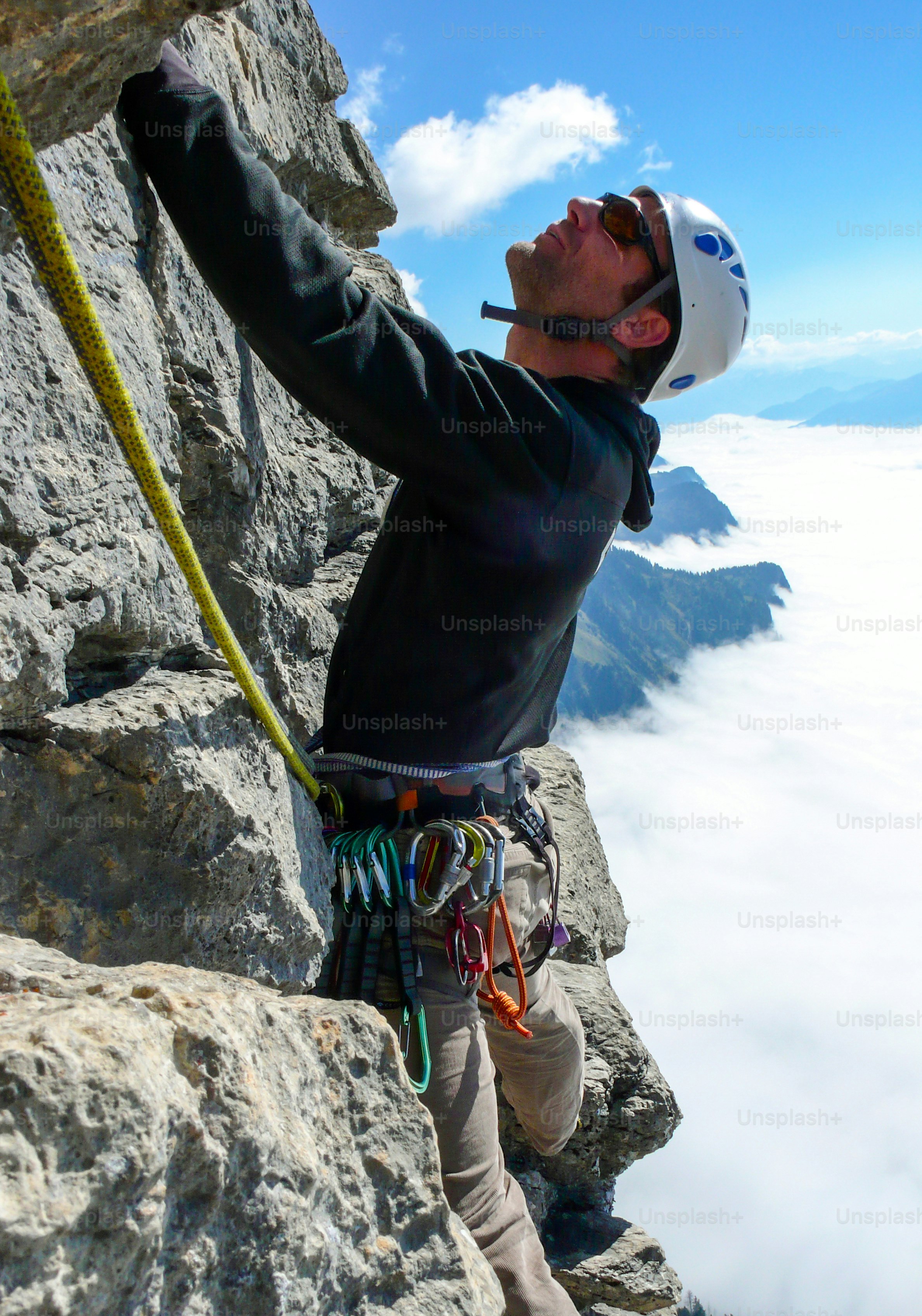 Male mountain guide smiling on a steep vertical rock climb in gorgeous ...