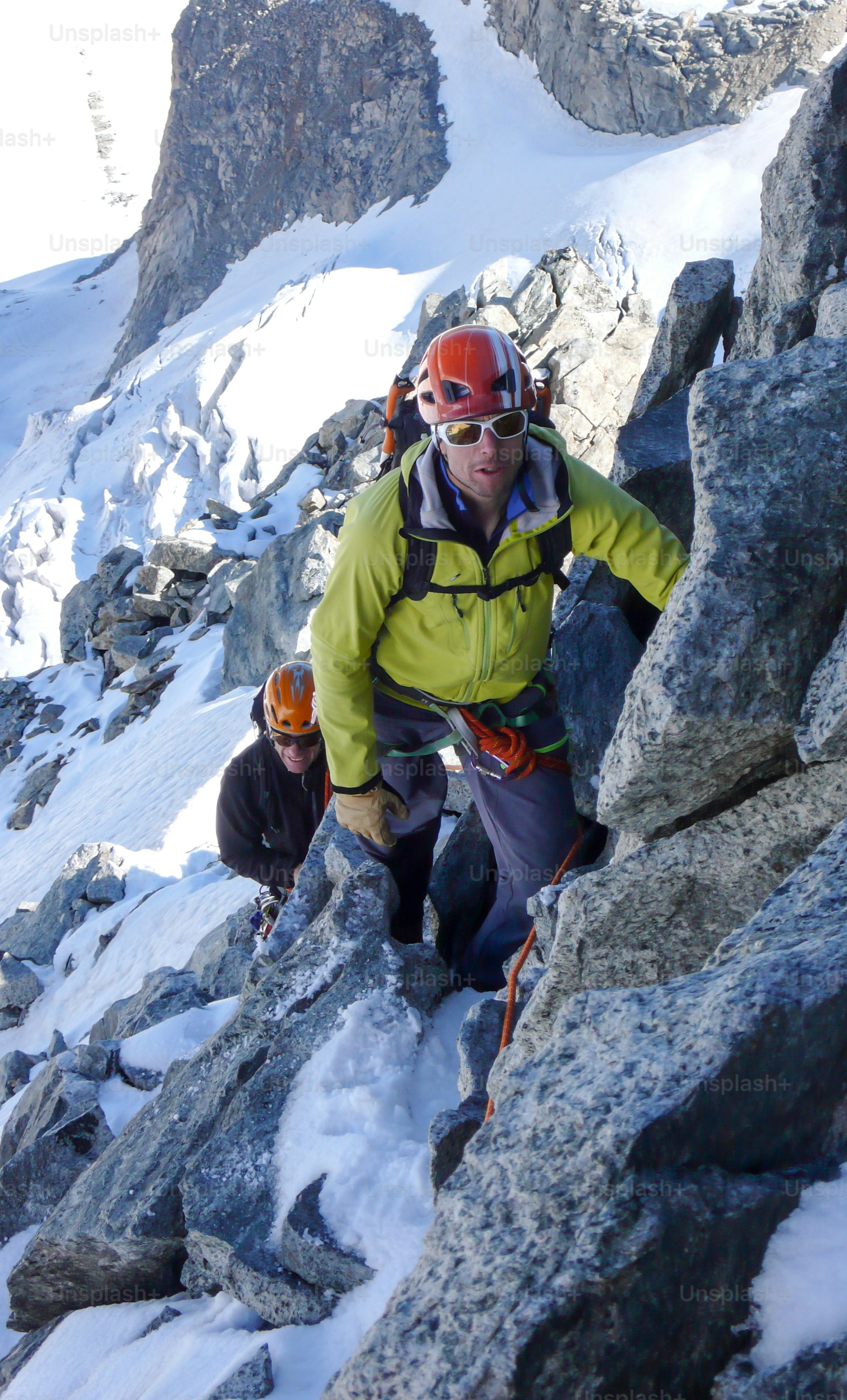 A mountain guide leading male client to the summit of a high alpine ...