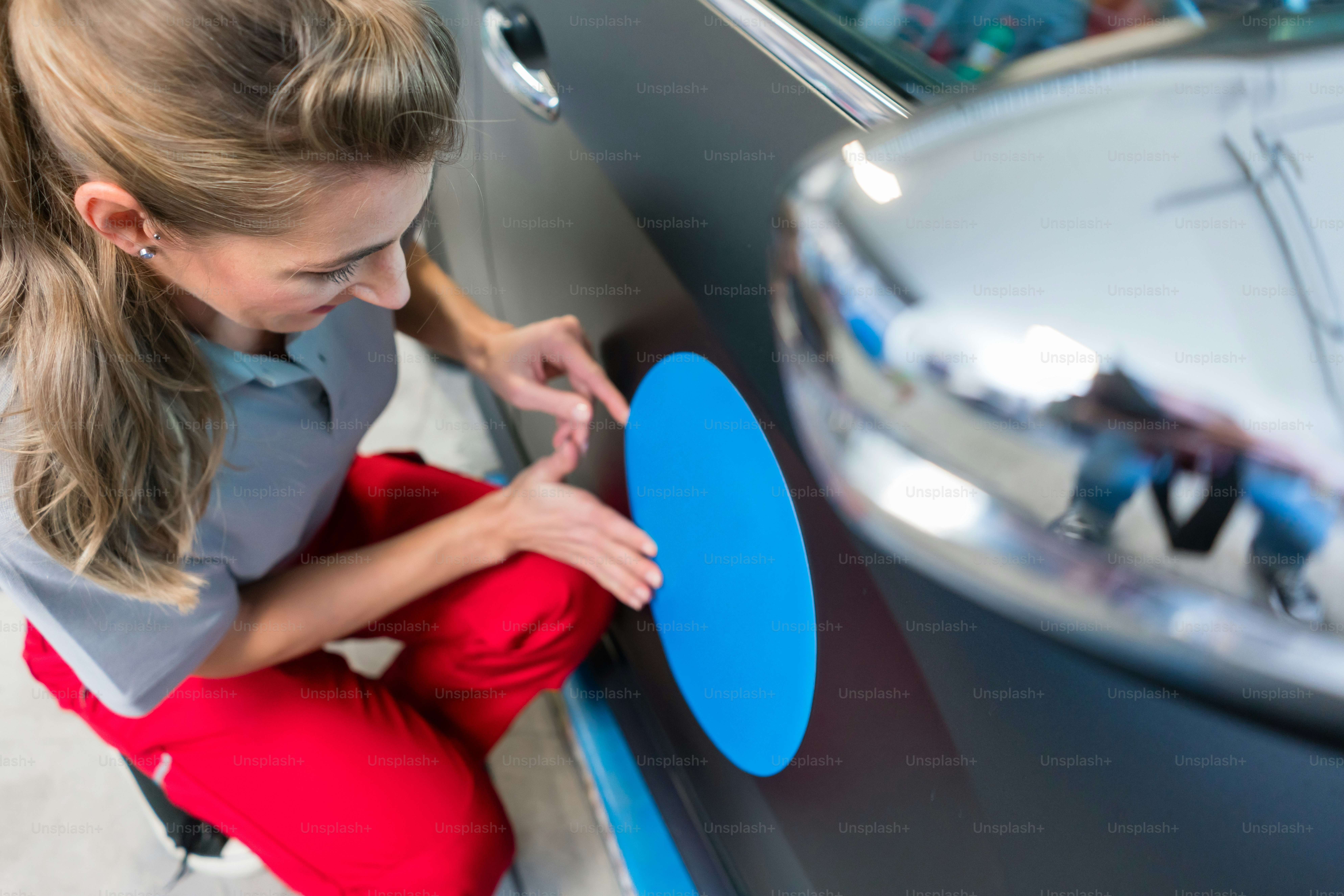 Woman putting promotional sticker with company slogan on a car photo ...