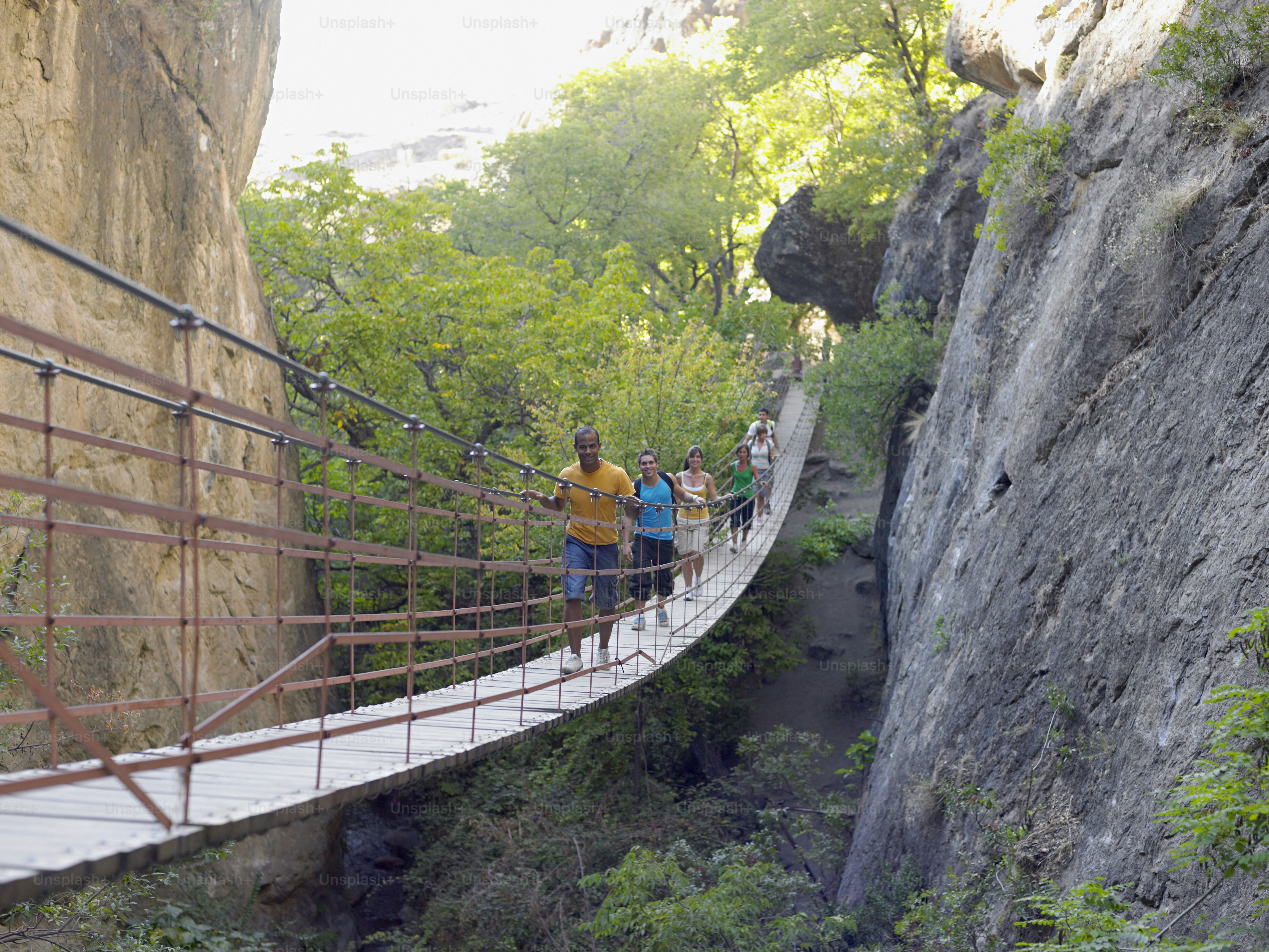 A group of people walking across a suspension bridge photo ...