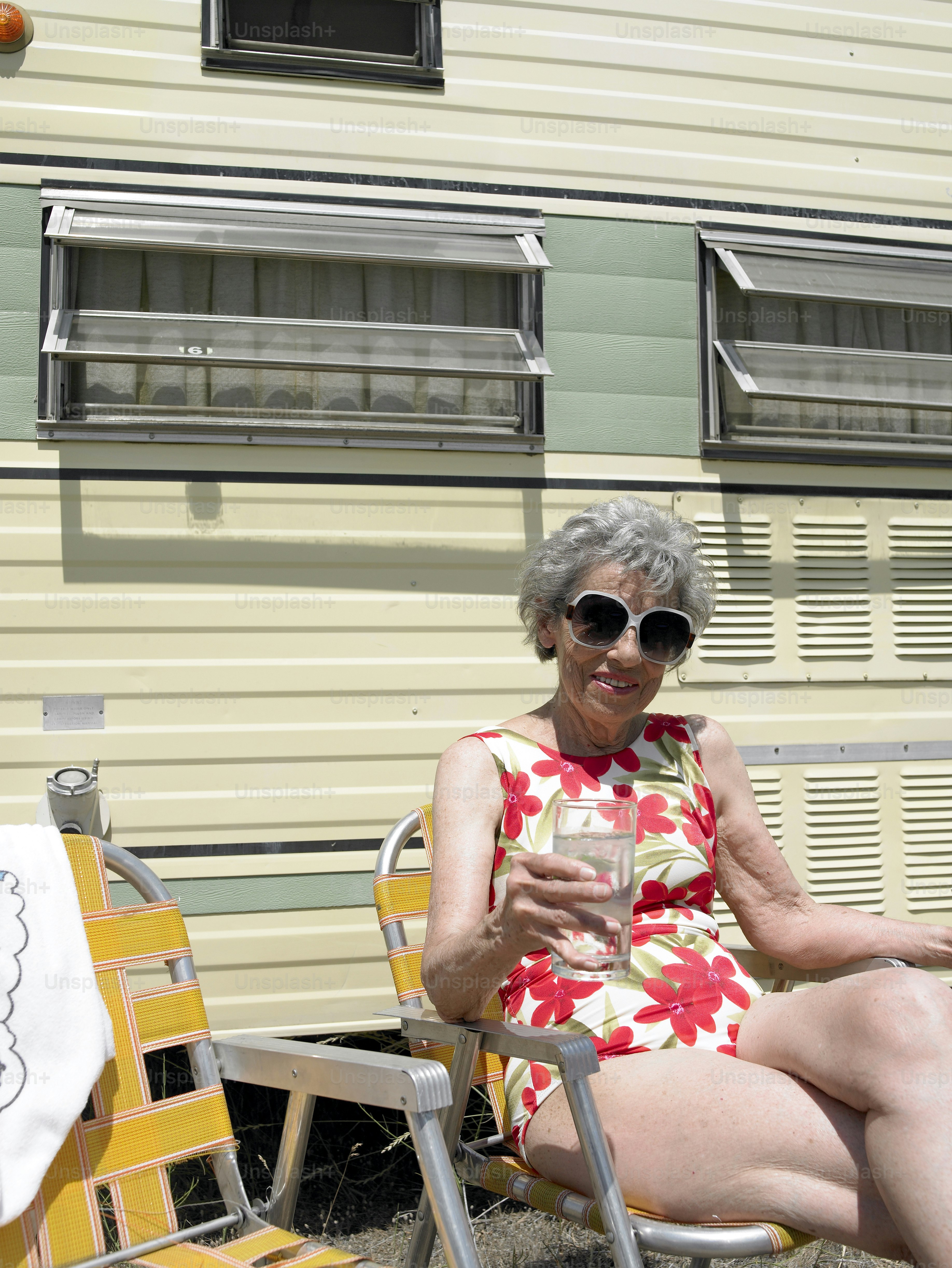 A woman sitting in a lawn chair next to a trailer photo – Day Image on ...