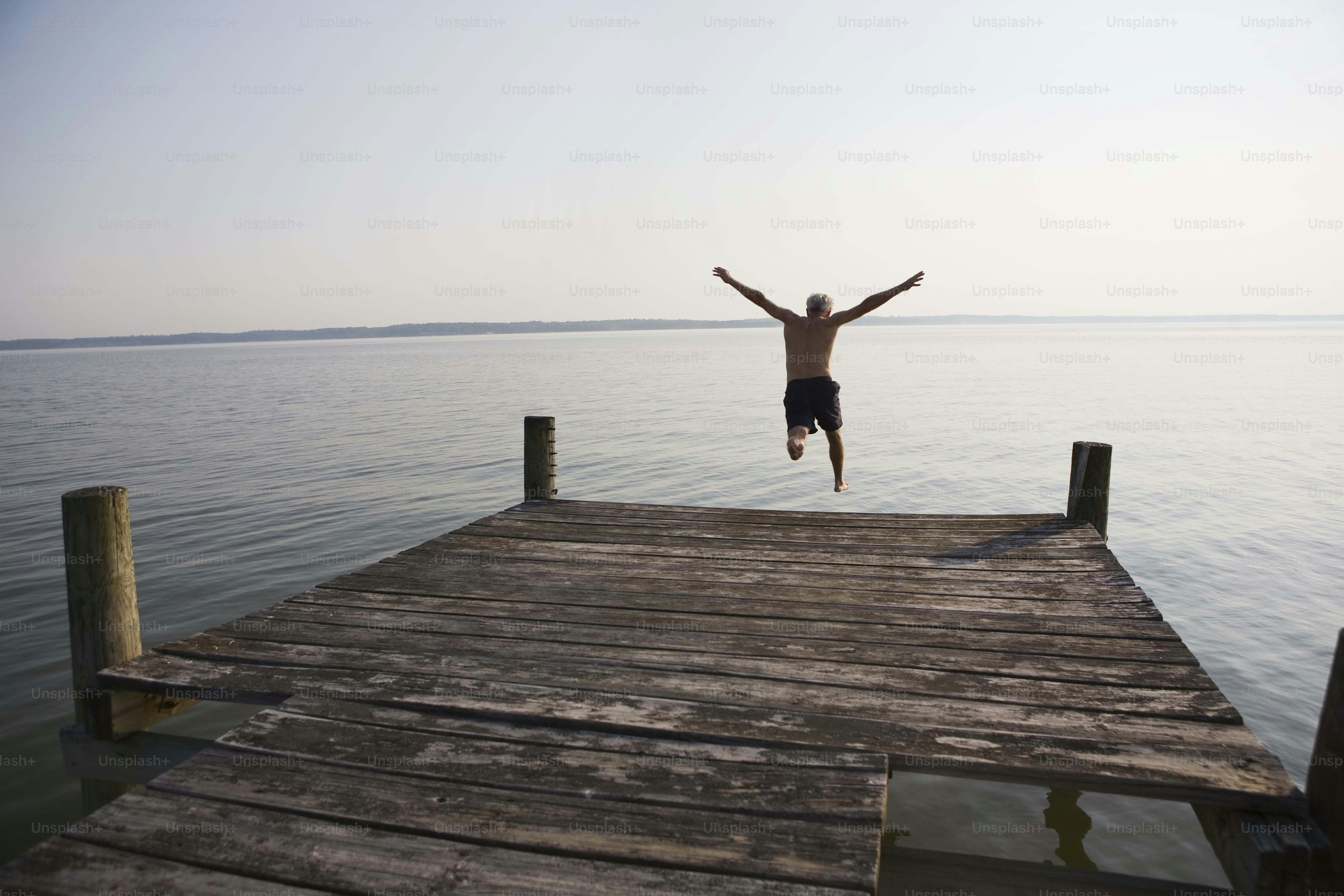 A man jumping off a dock into the water photo – Dock Image on Unsplash