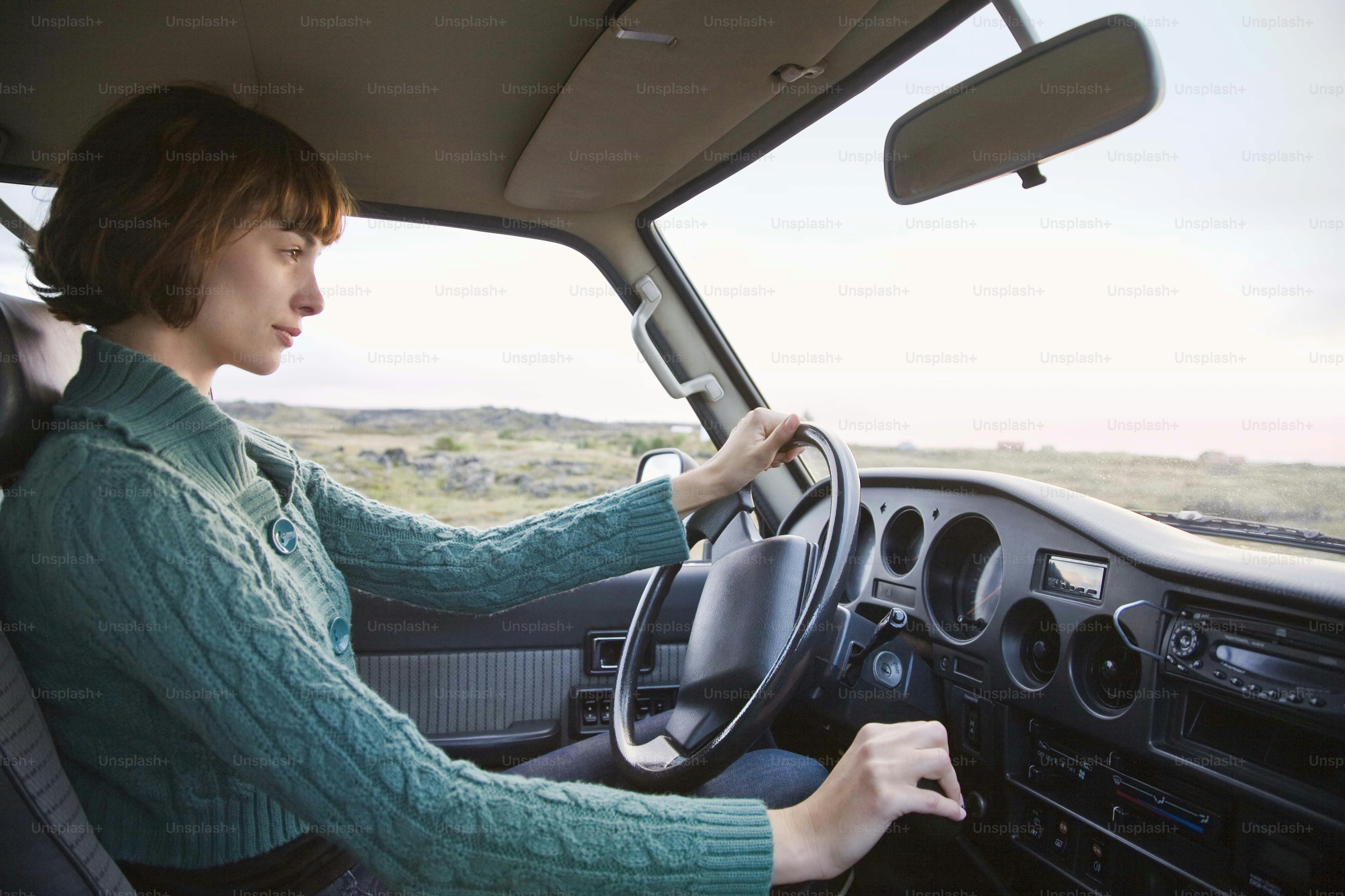 A woman driving a car on a rural road photo – One person Image on Unsplash