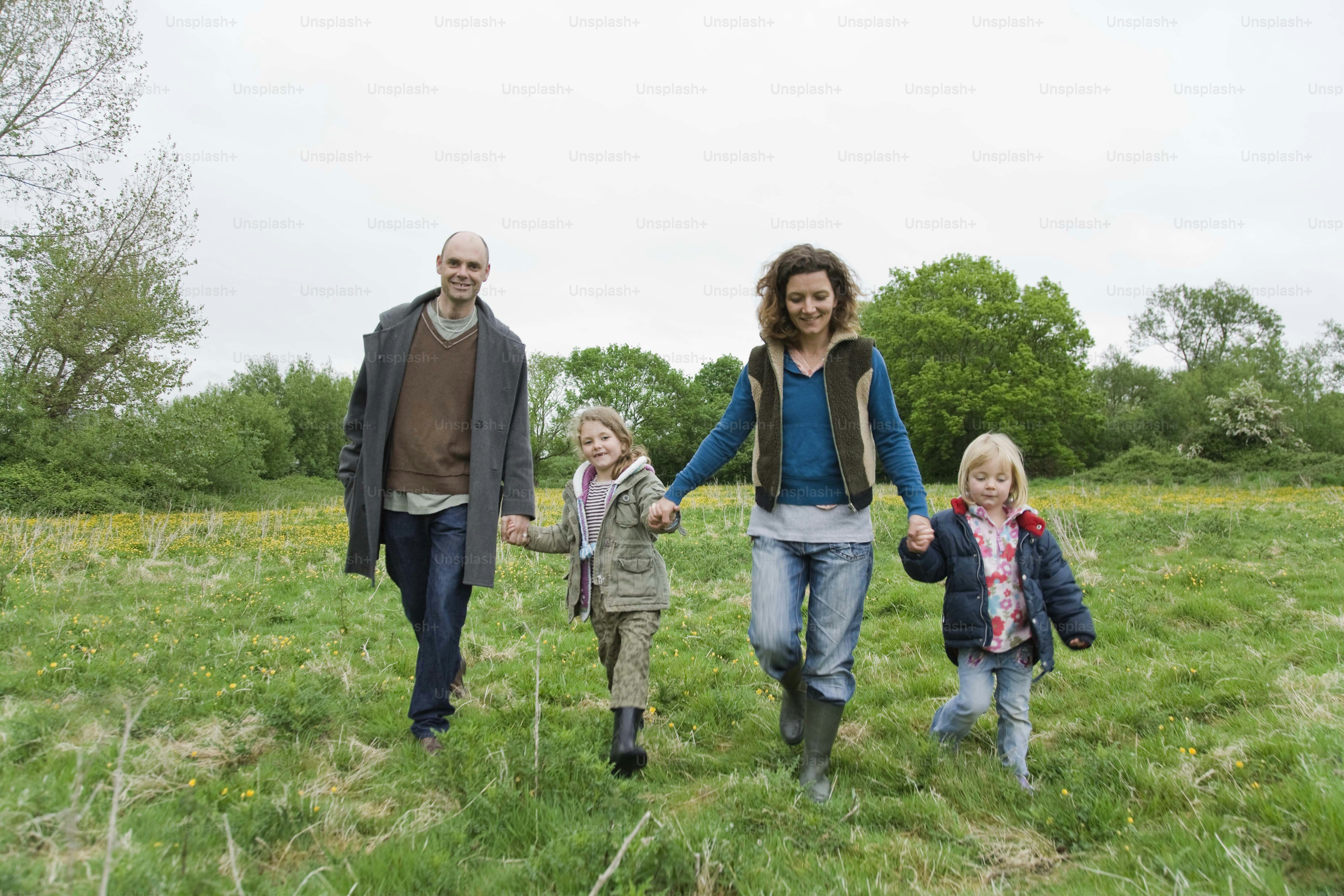 A family walking through a field holding hands photo – 2-3 years Image ...
