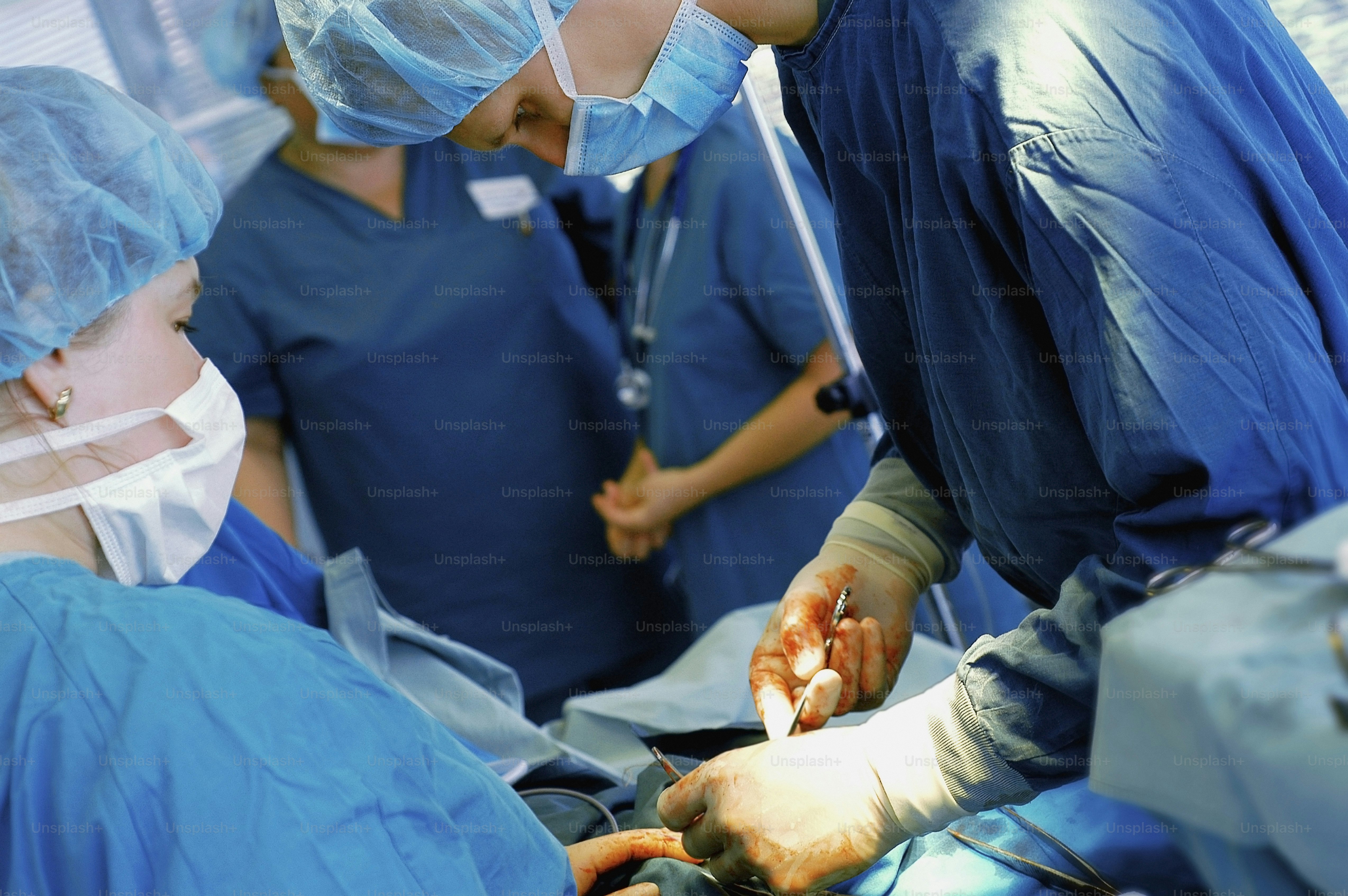A group of doctors performing surgery on a patient photo – Hospital ...