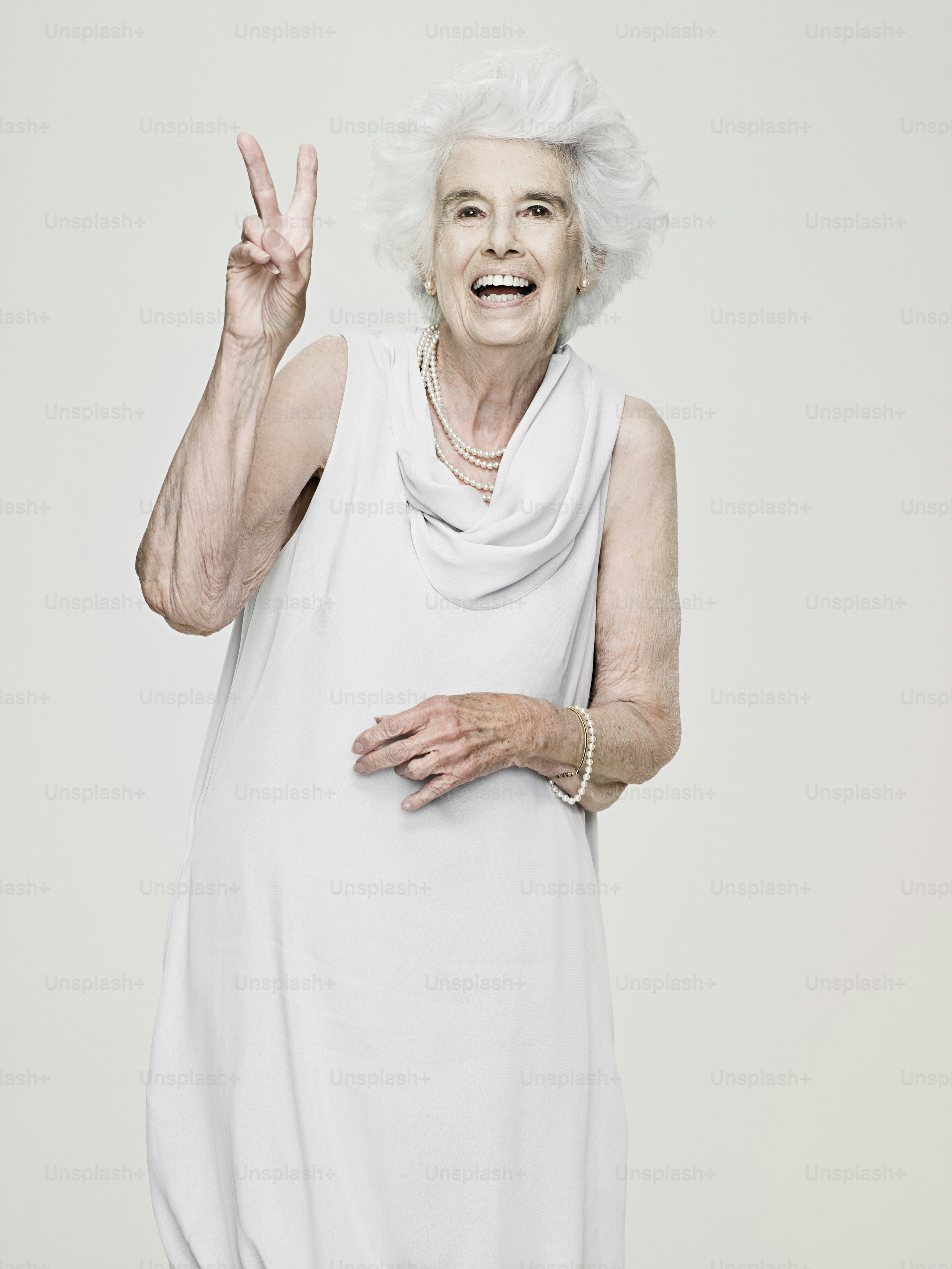 An older woman making a peace sign with her hand photo – Senior adult ...