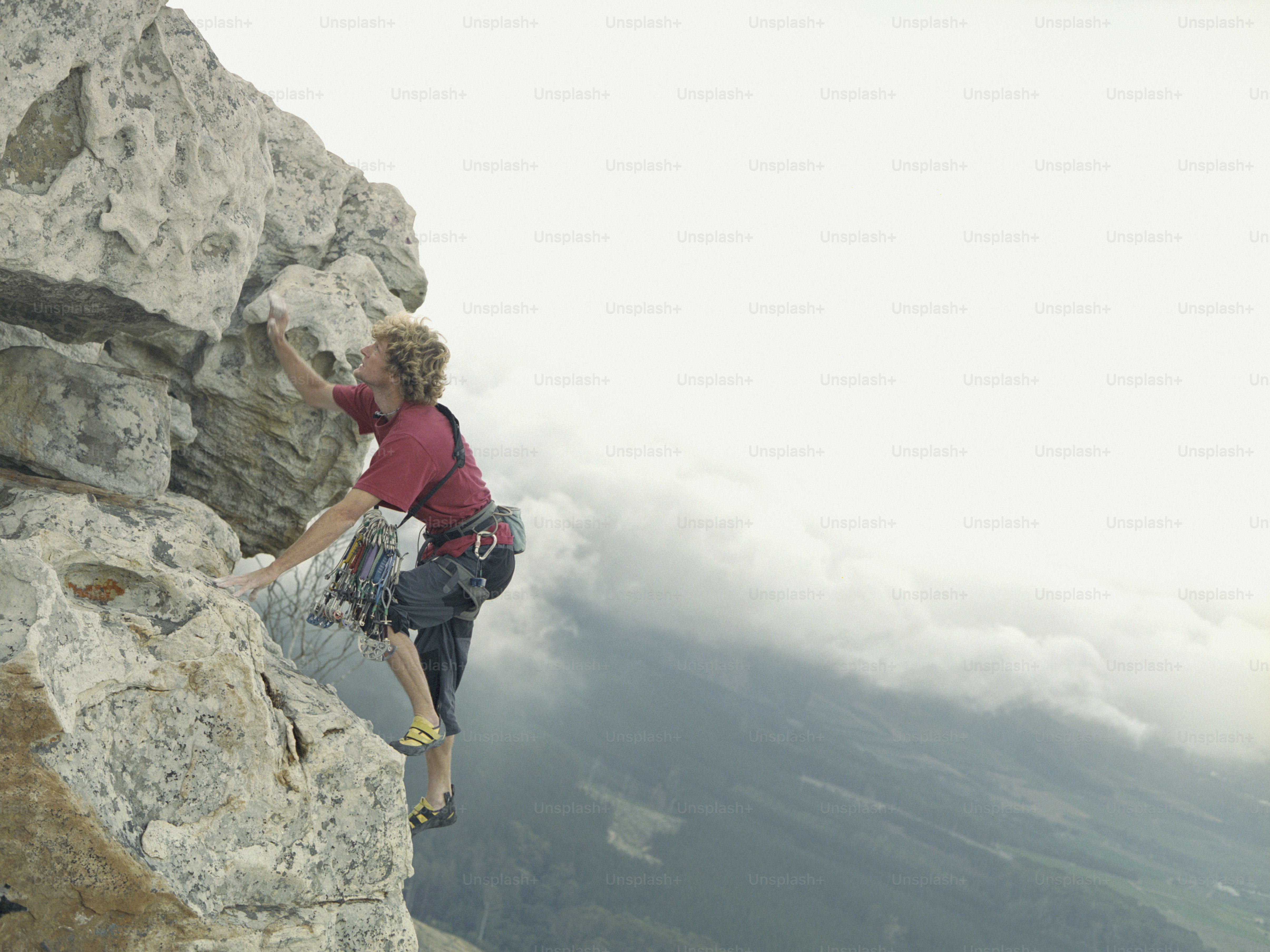 A man climbing up the side of a mountain photo – Young men Image on ...