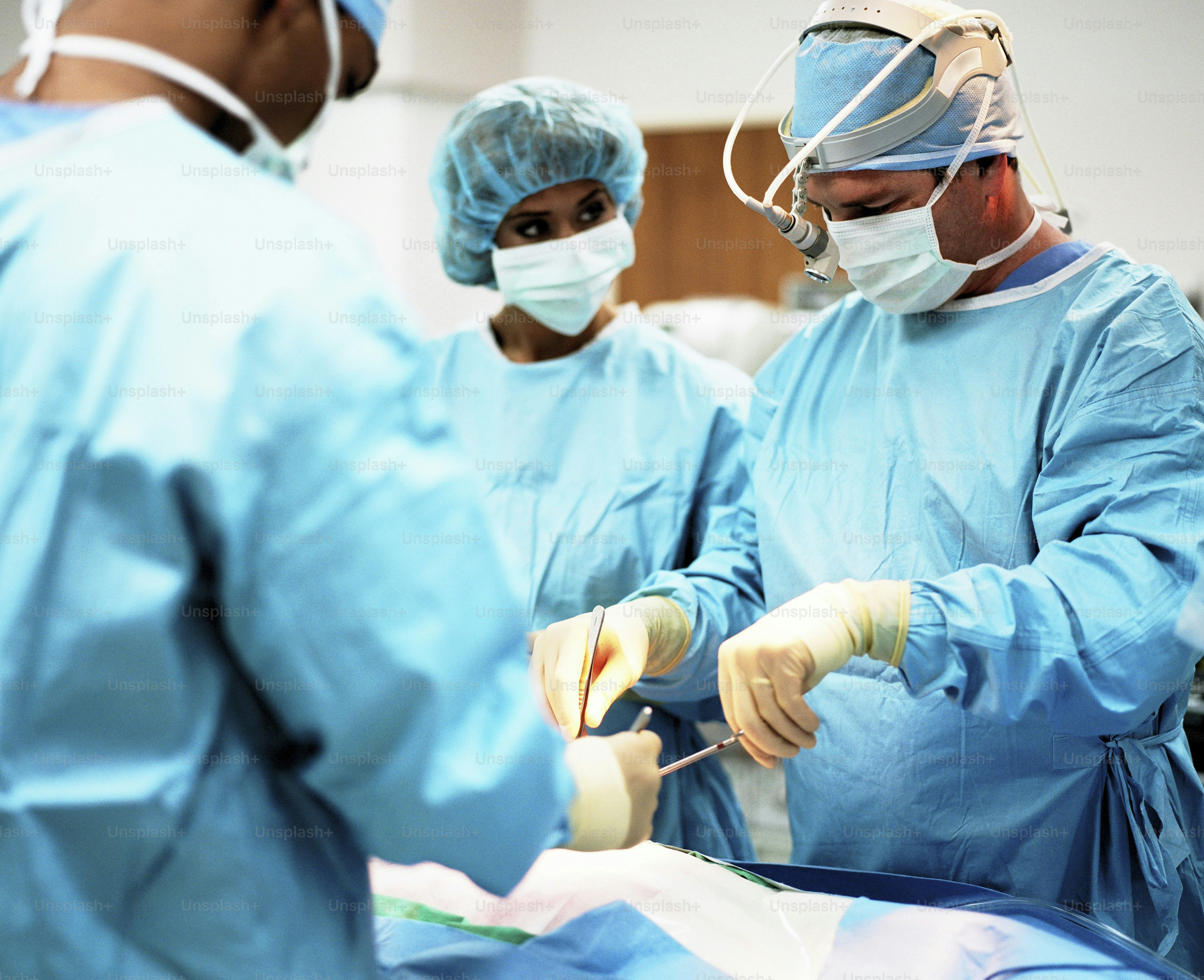 A group of doctors performing surgery on a patient photo – Indoors ...