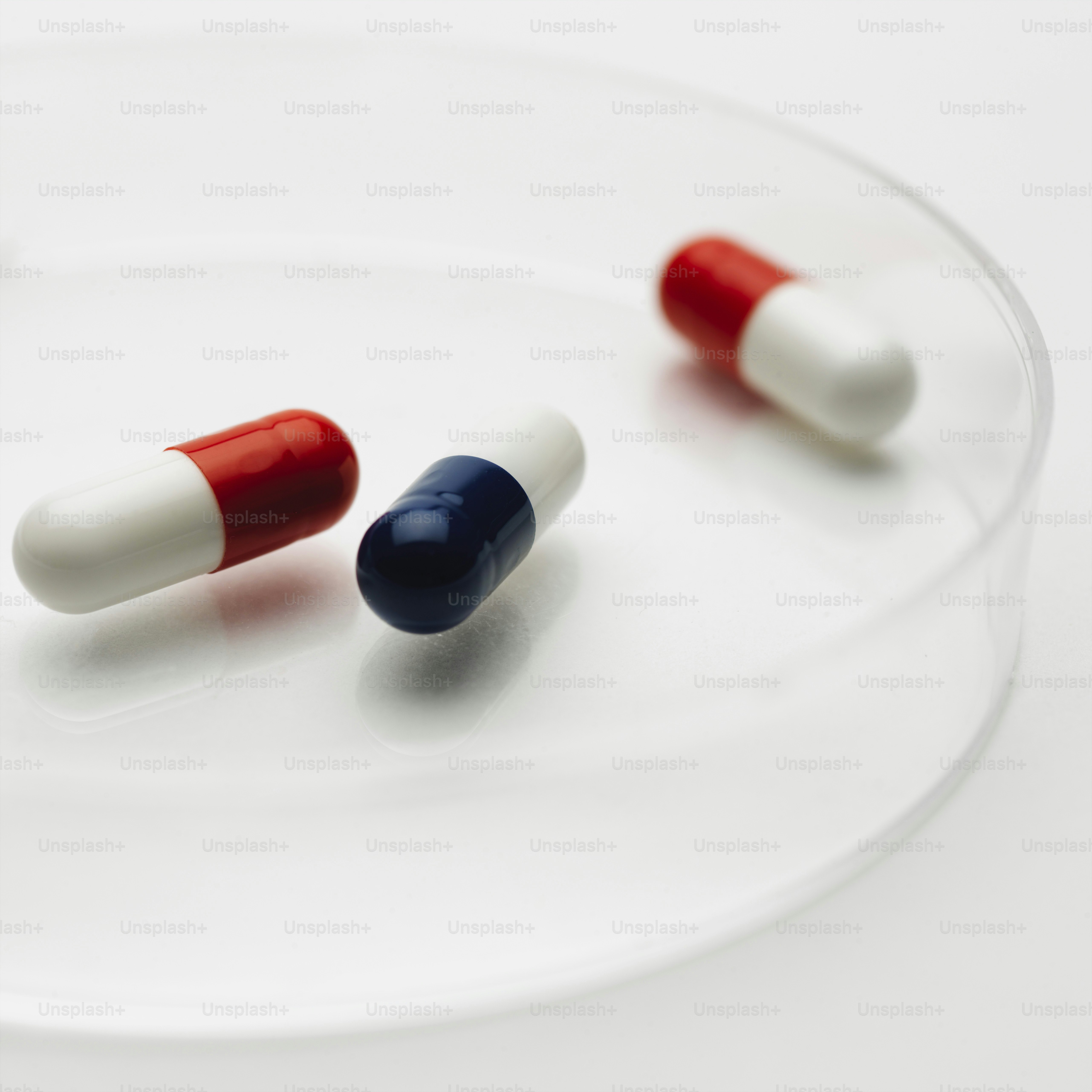 Three pills sitting on top of a white plate photo – Four objects Image ...