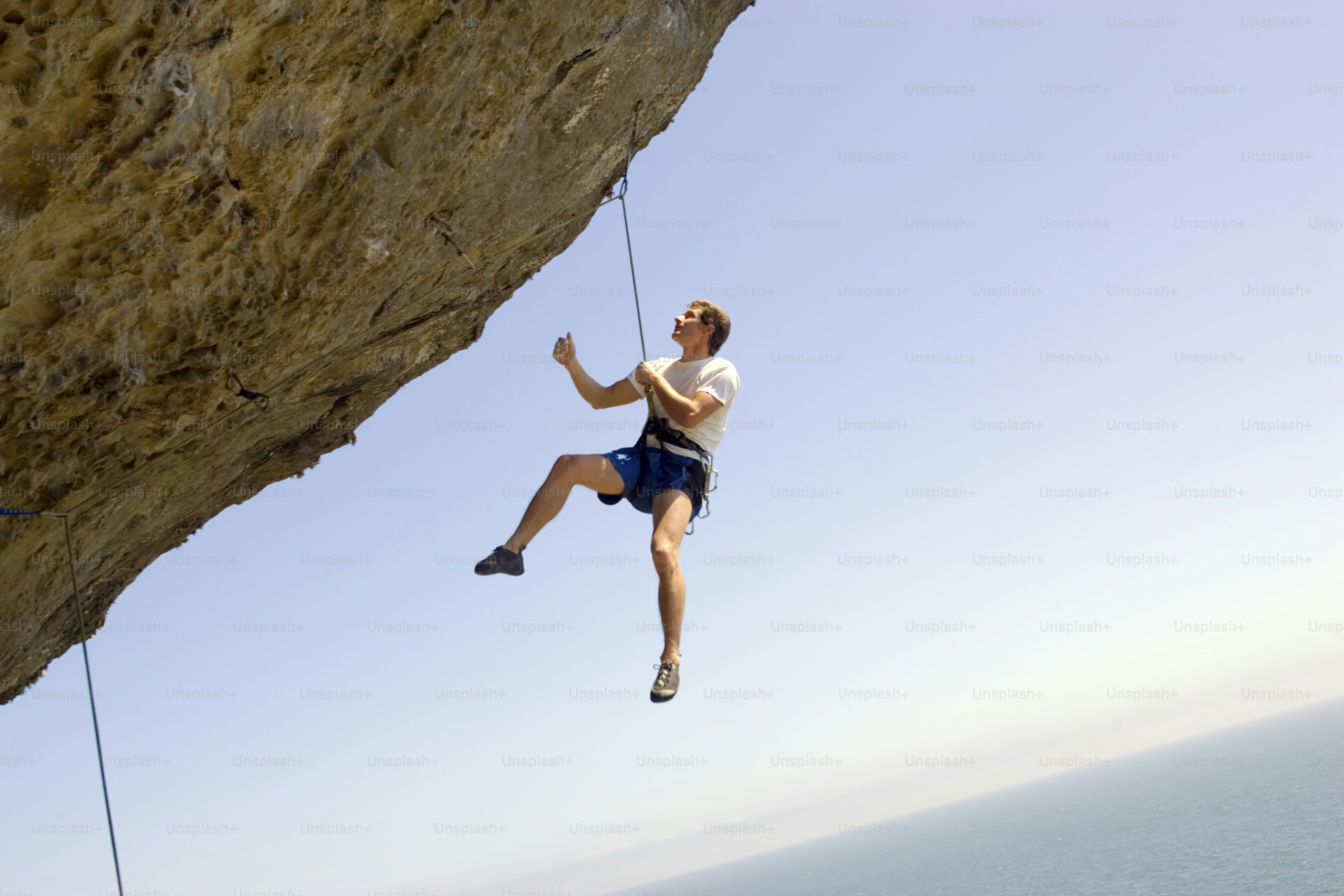 A man hanging from a rope on top of a cliff photo – Men Image on Unsplash