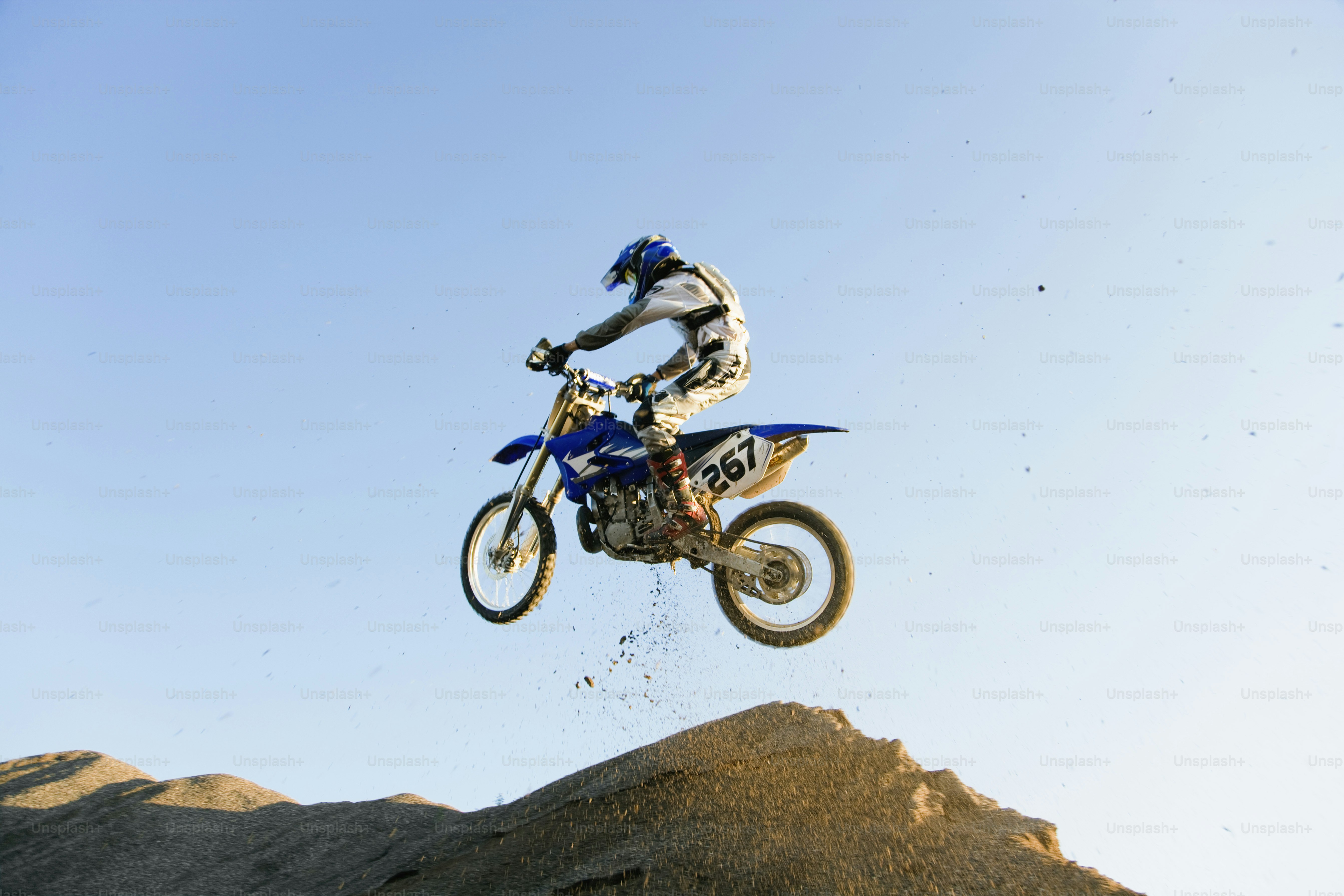 A man riding a dirt bike on top of a dirt field photo – Motorcycle ...