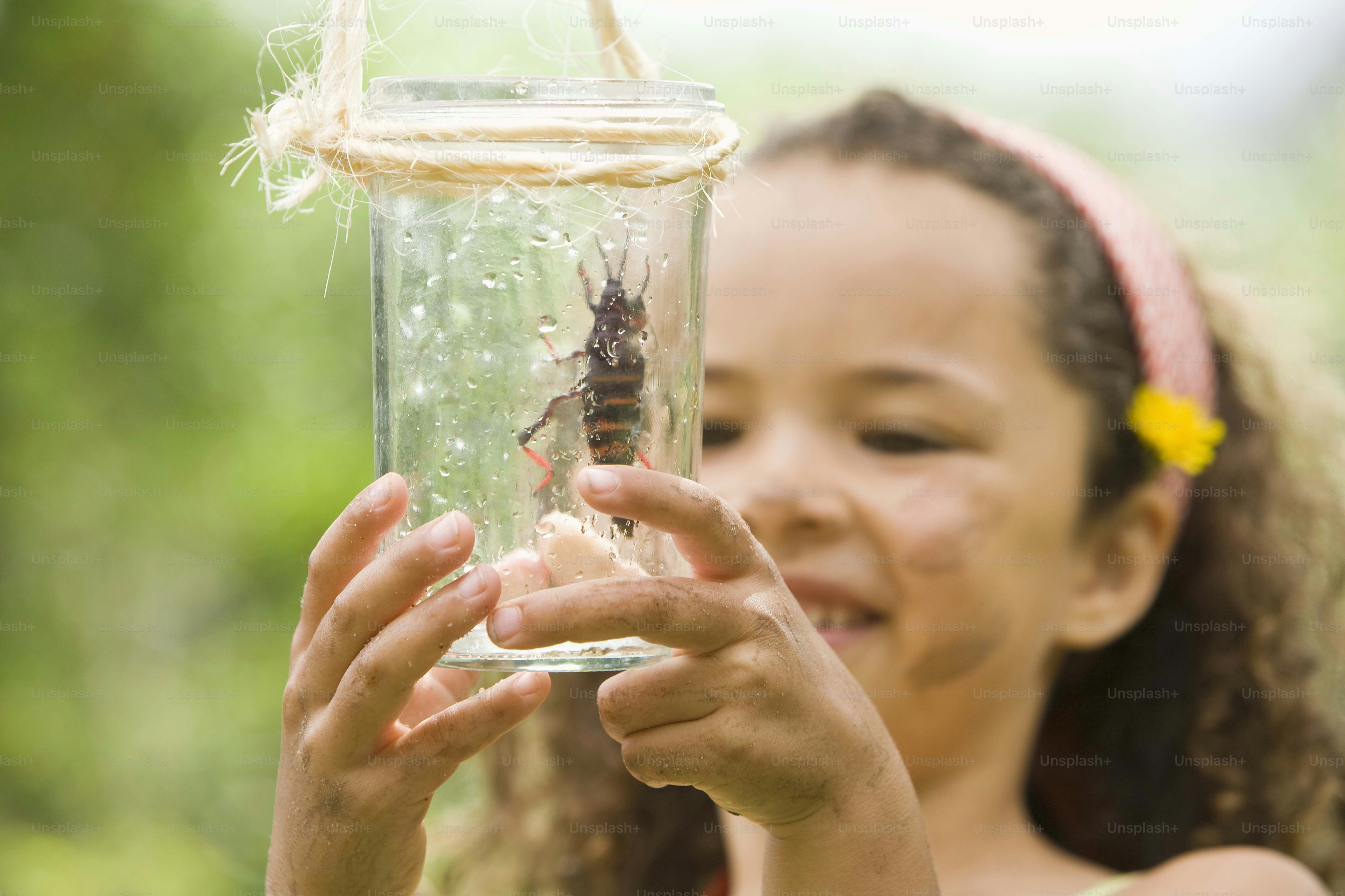 Foto Una niña sosteniendo un frasco de vidrio con un insecto dentro de ...