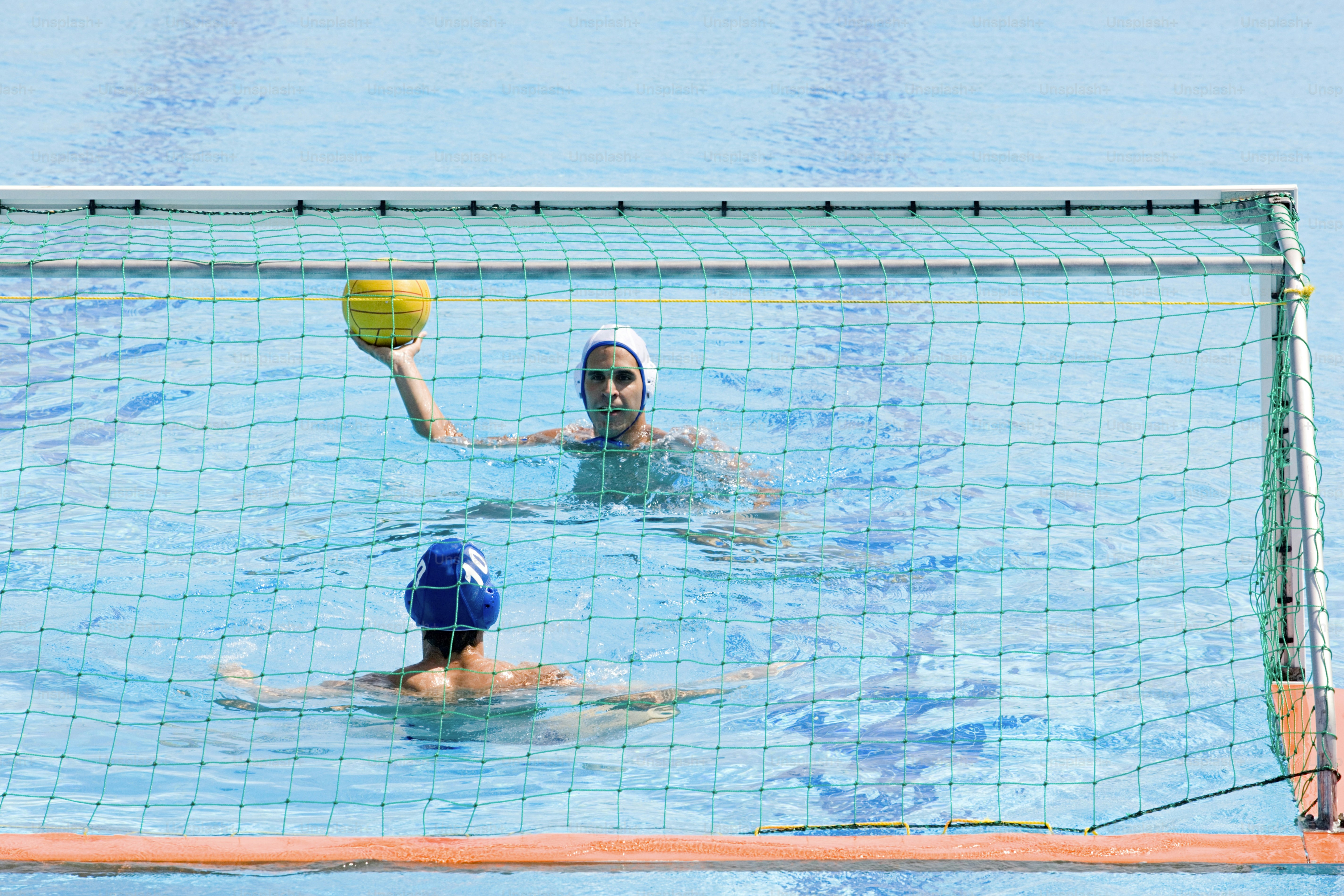 A couple of people playing a game of water polo photo – Water polo ...