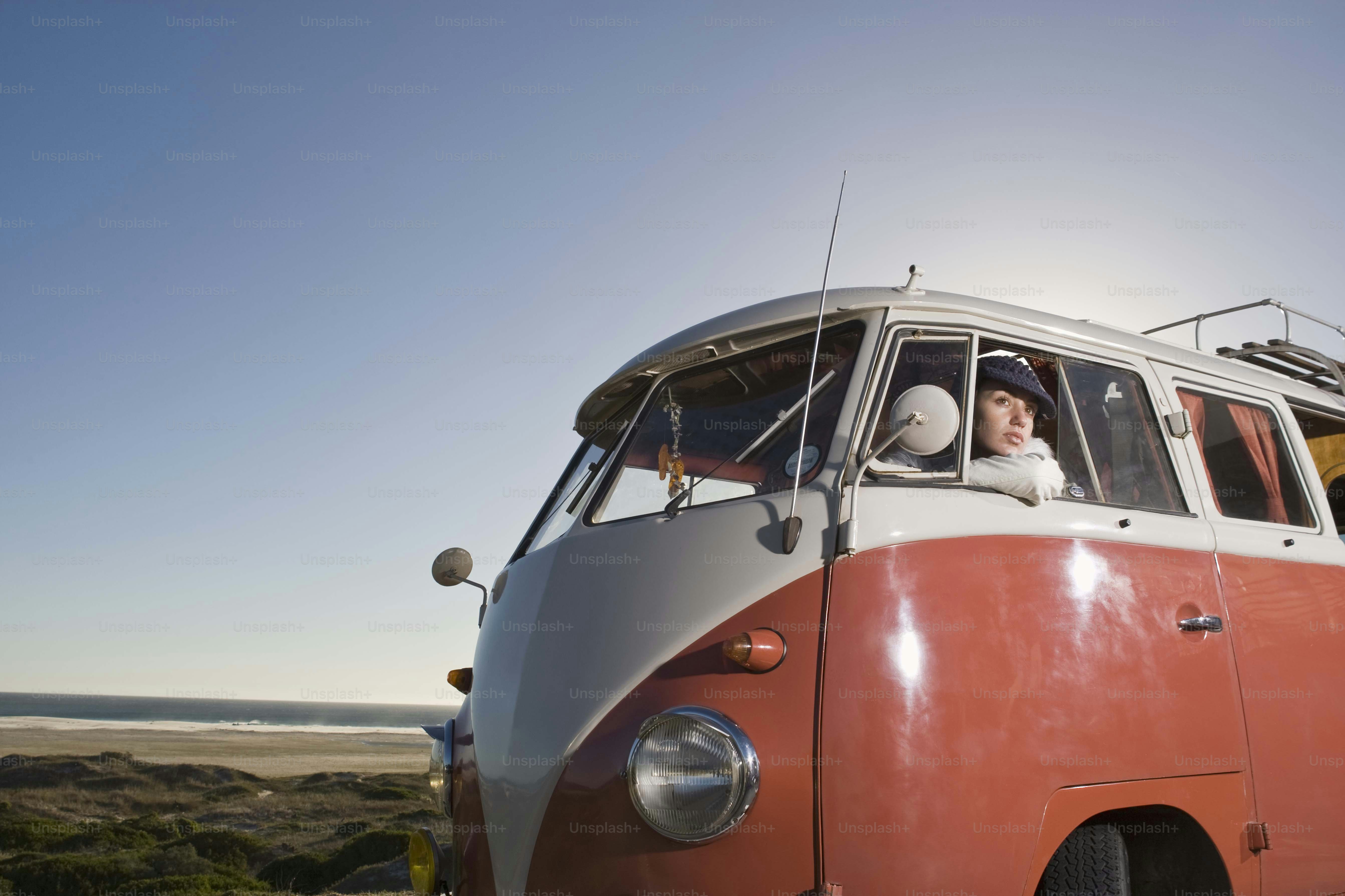 A man sitting in the front of an orange and white van photo – Minibus ...