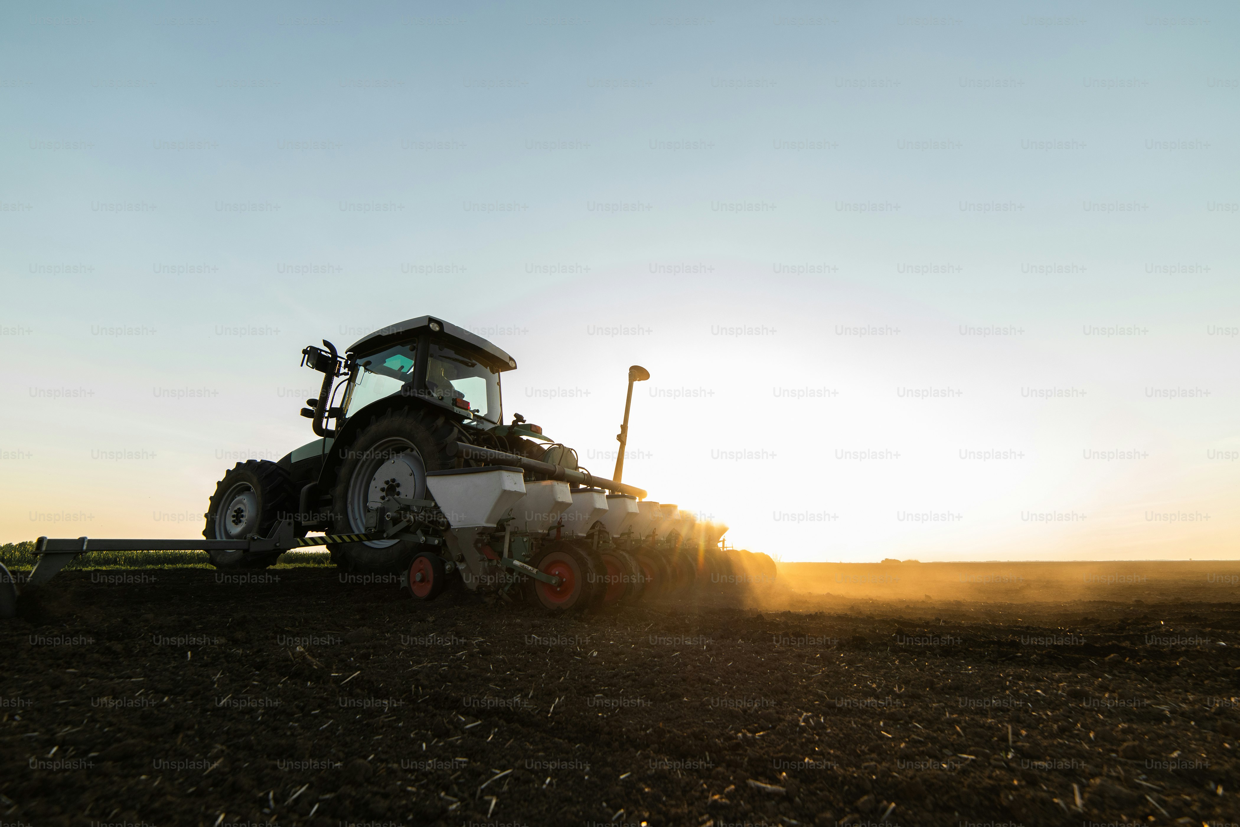 Farmer with tractor seeding - sowing crops at agricultural field ...