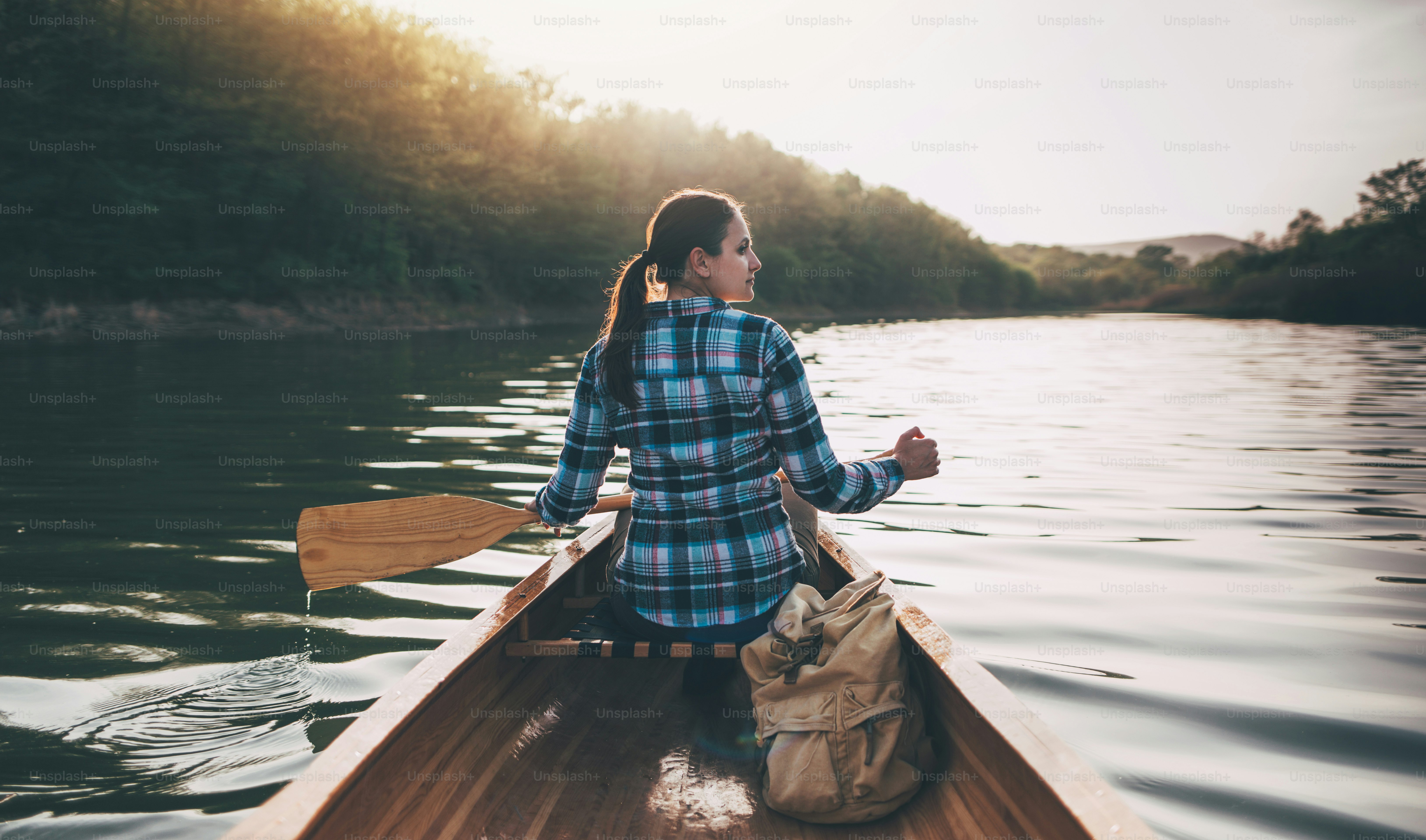 Foto Vista trasera de una chica hipster remando en la canoa en el lago ...