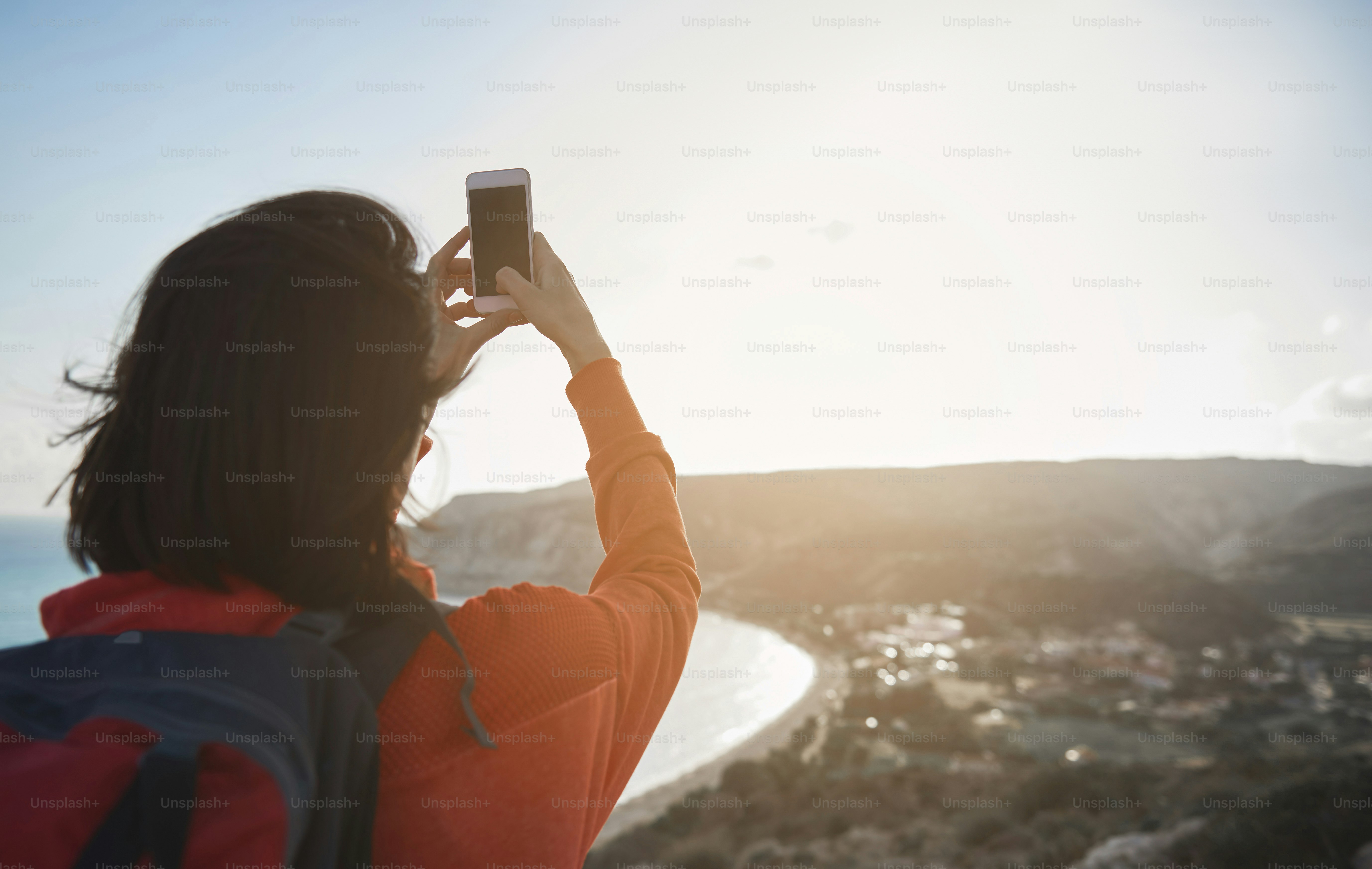 Back of woman with backpack photographing coast and sea. Copy space in ...