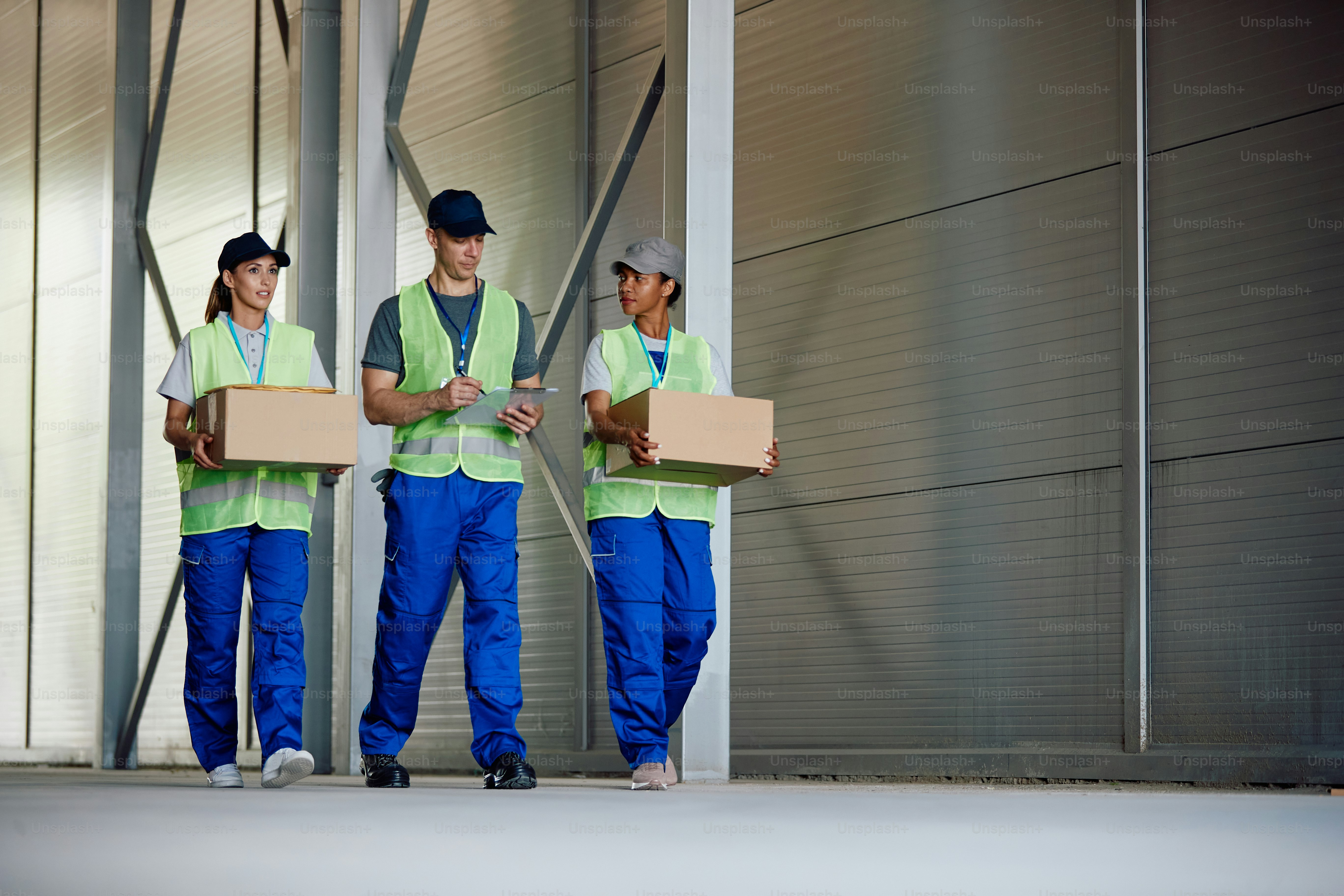 Warehouse manager analyzing check list while female workers are ...