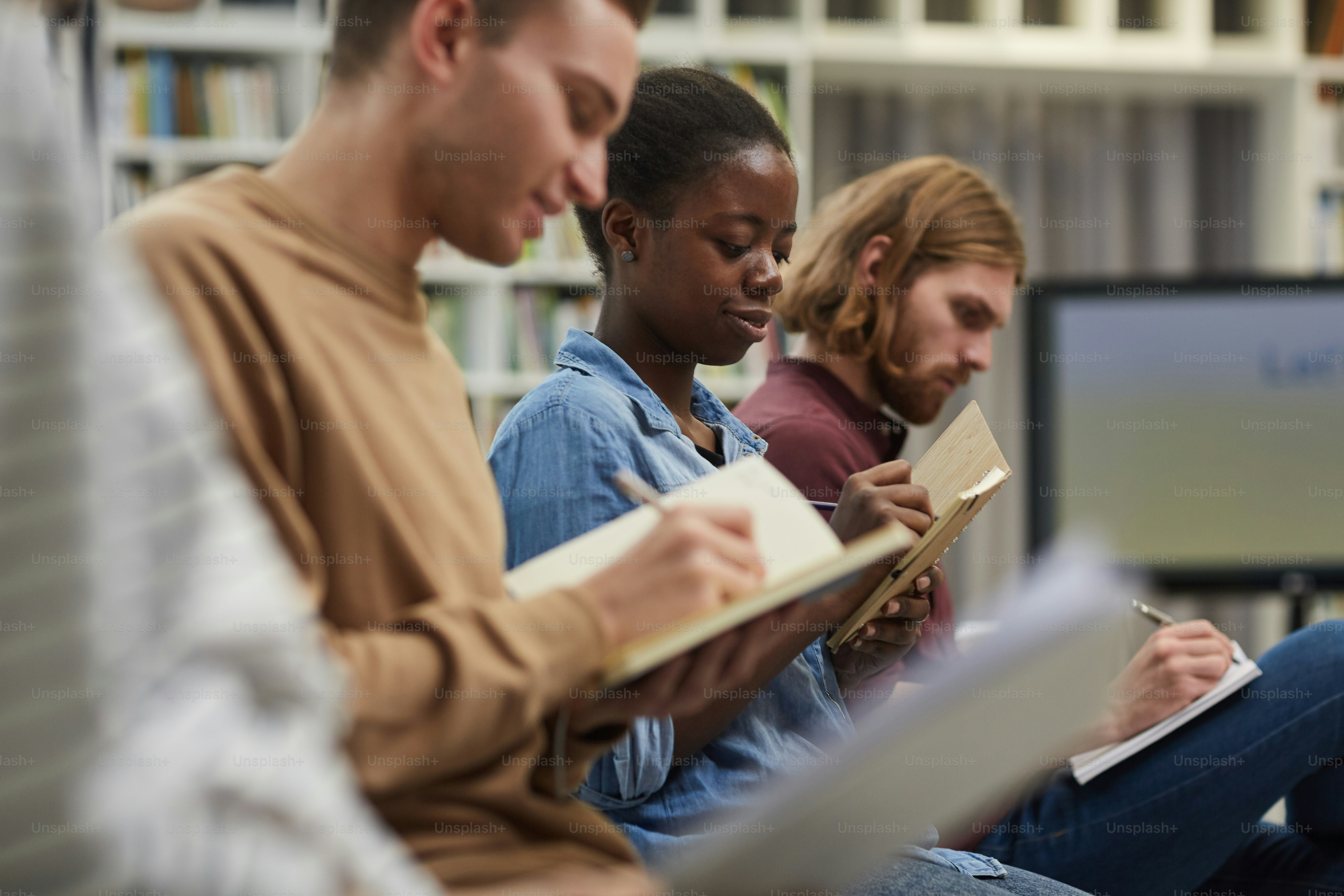 Group of students sitting and writing in their notebooks during lecture ...