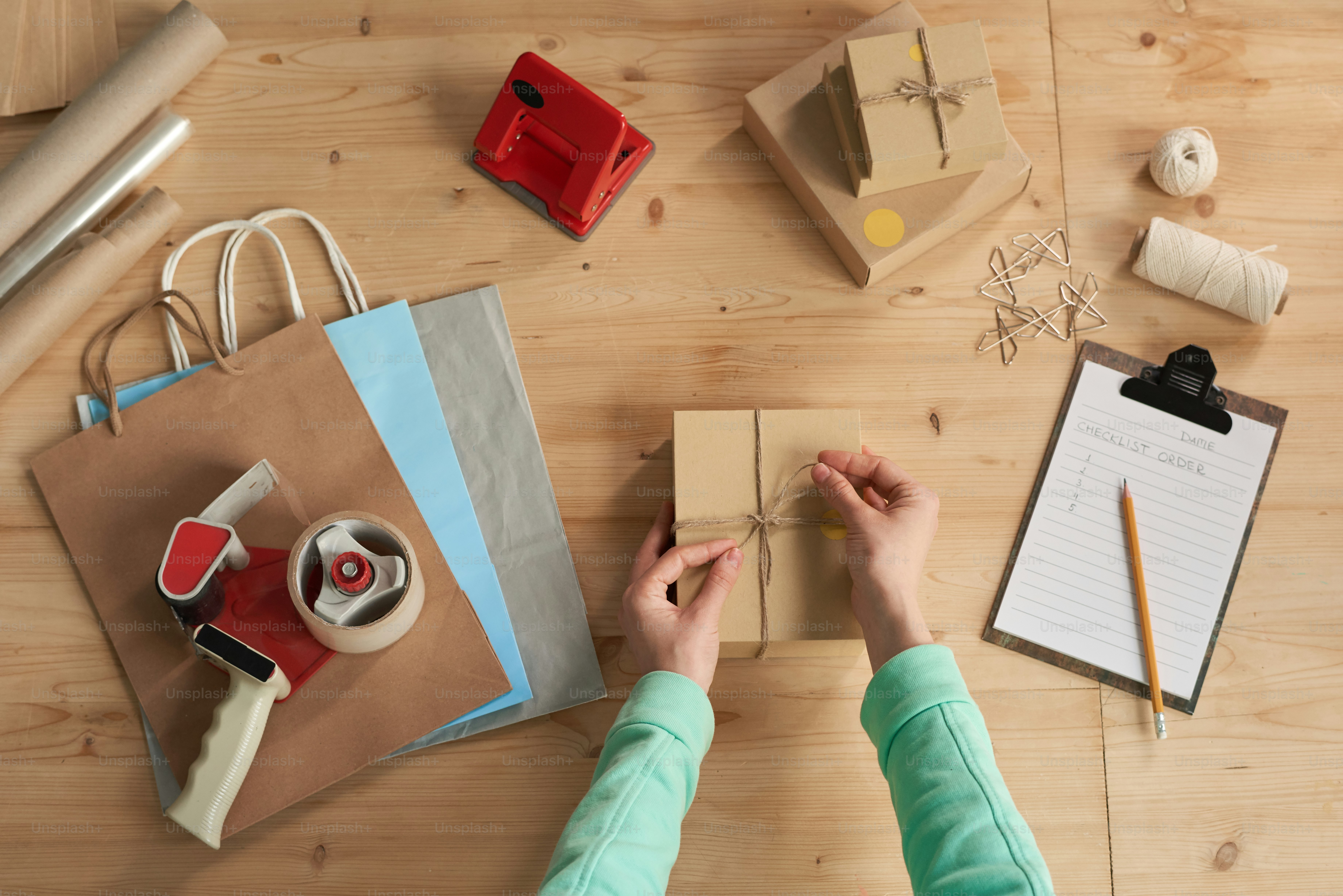 Close-up of woman packing the present into the cardboard box and tying ...