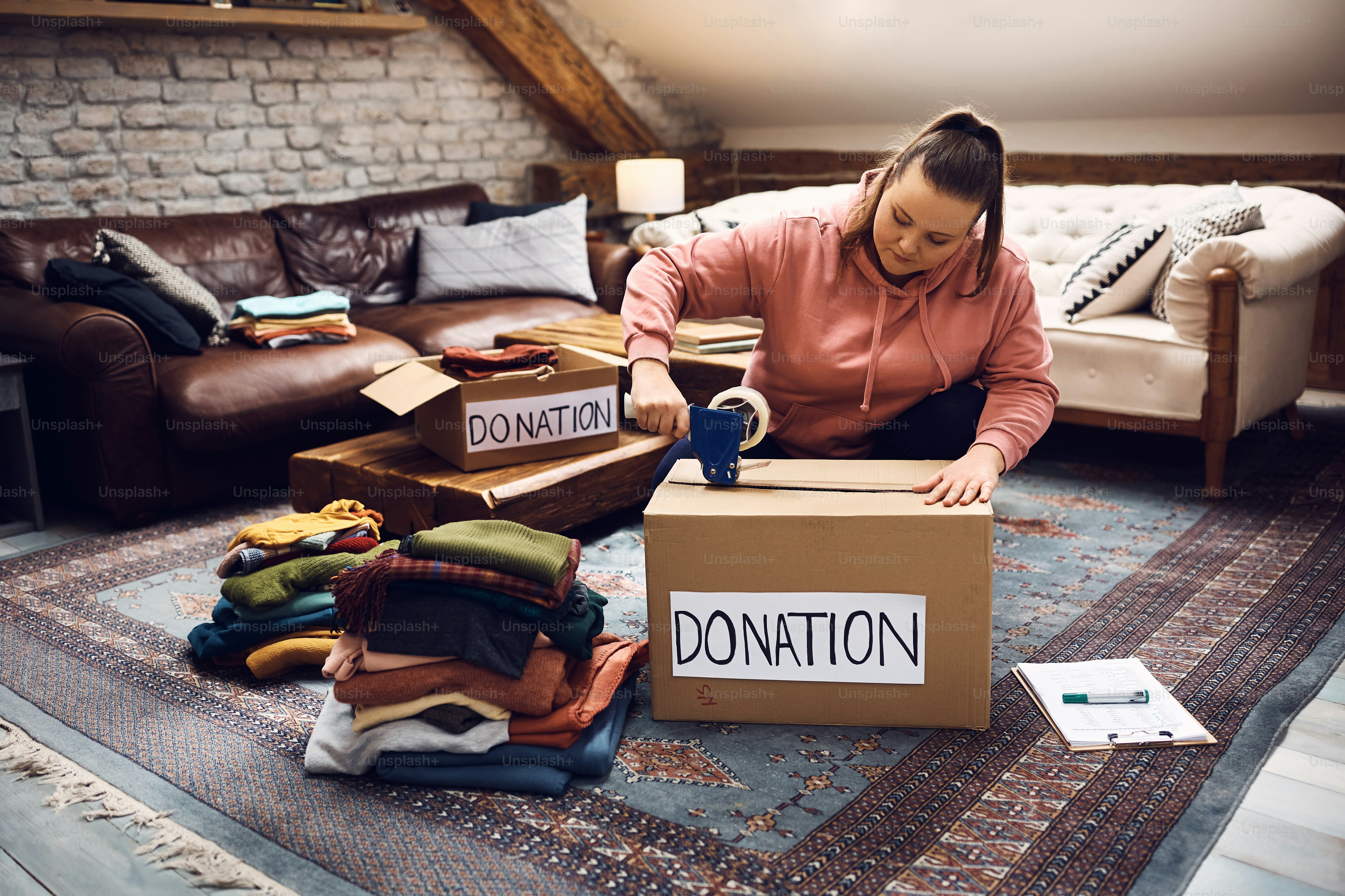 Close-up of woman checking list of donated clothes for charity while ...