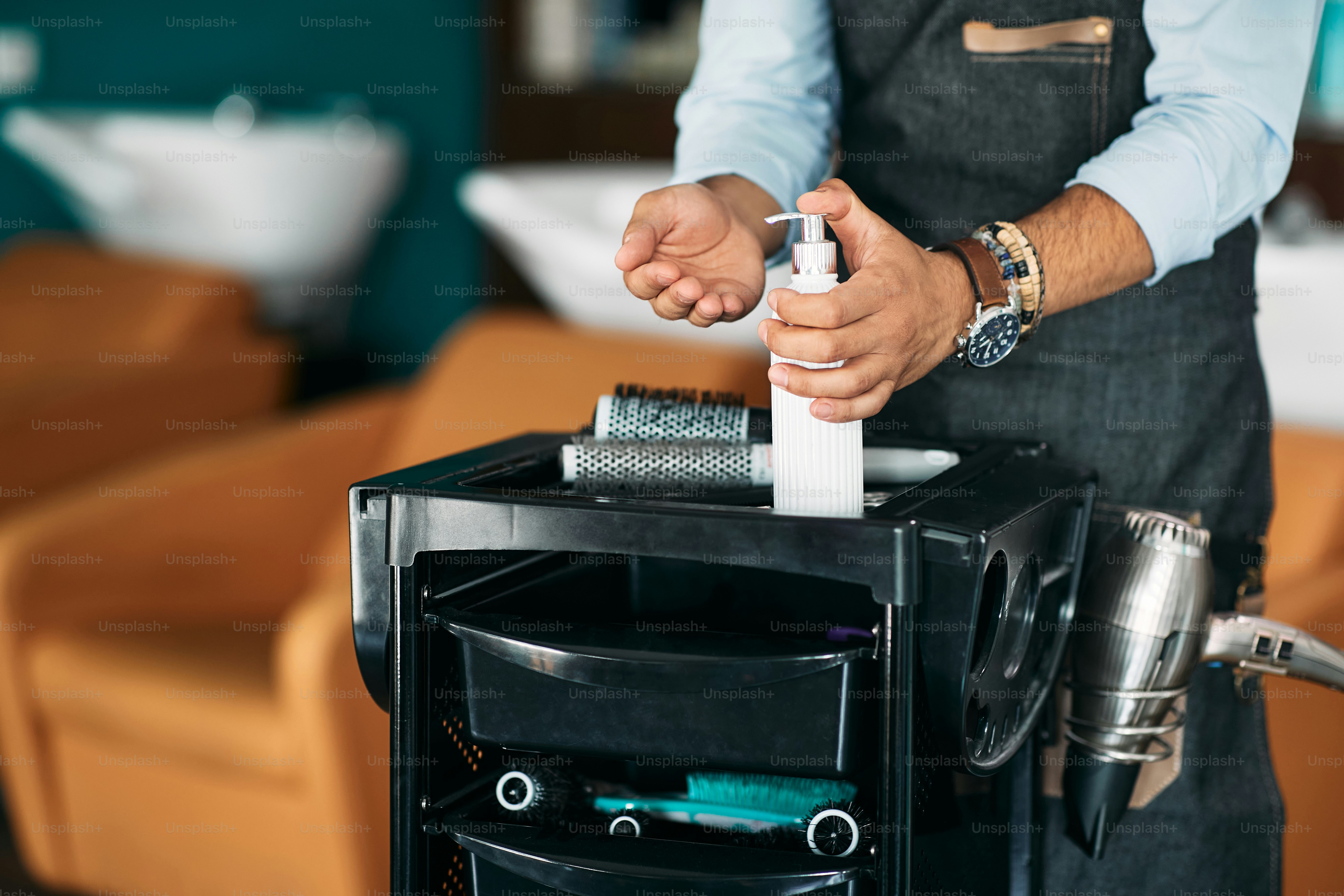 Close-up of hairstylist cleaning hairbrushes and spraying them with ...