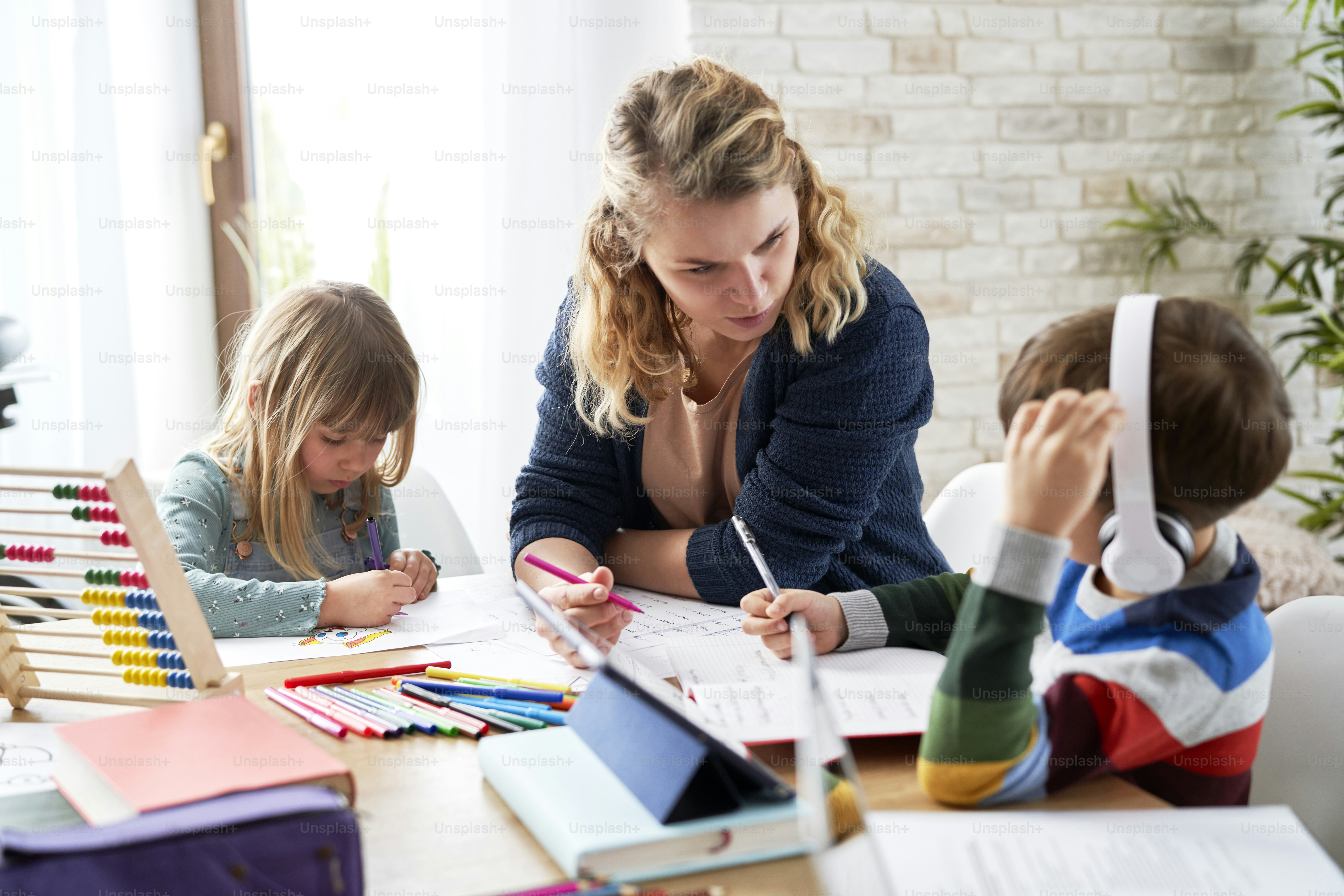 Young mother helping children during making homework photo ...