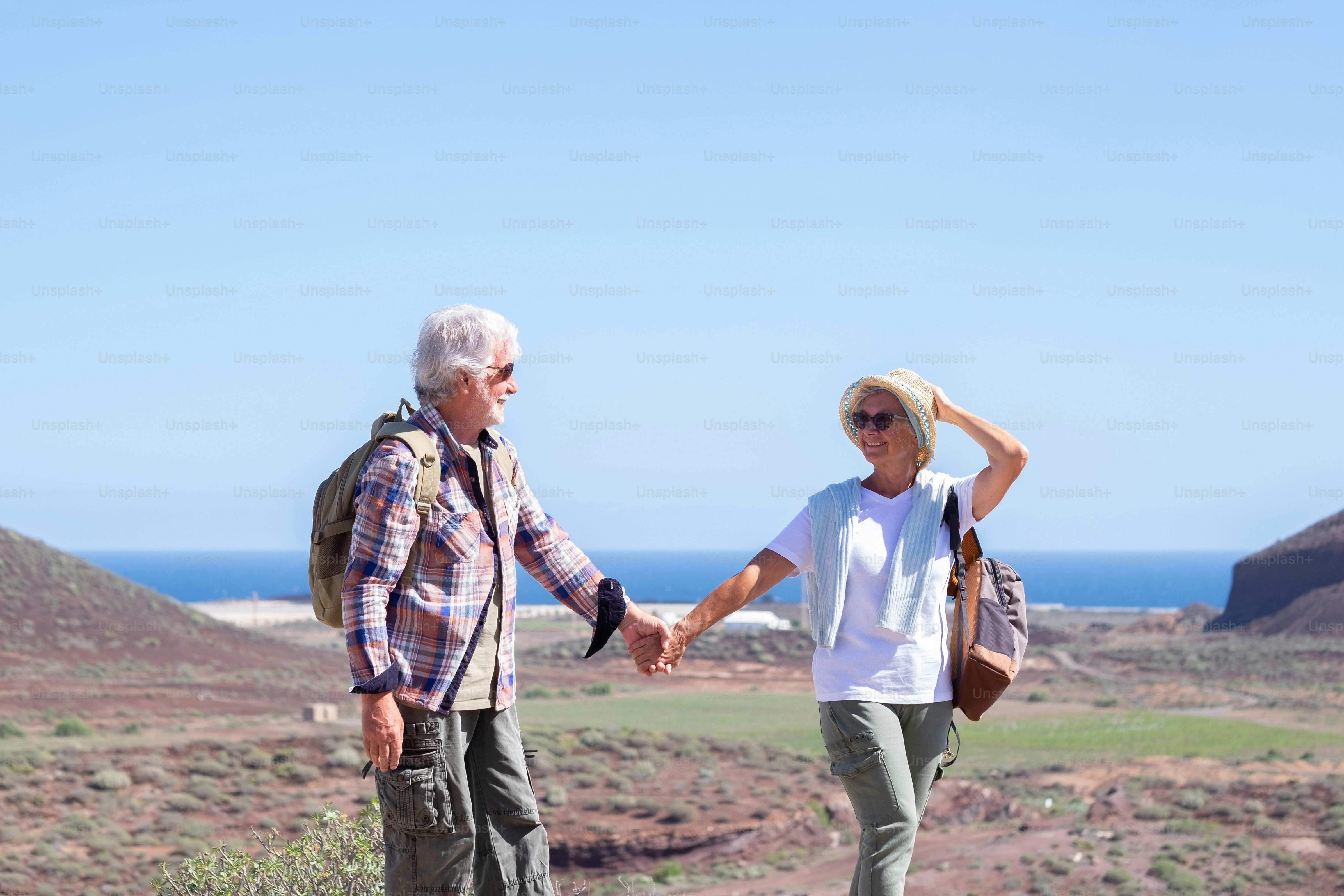 Active smiling senior couple with backpacks in outdoors excursion ...