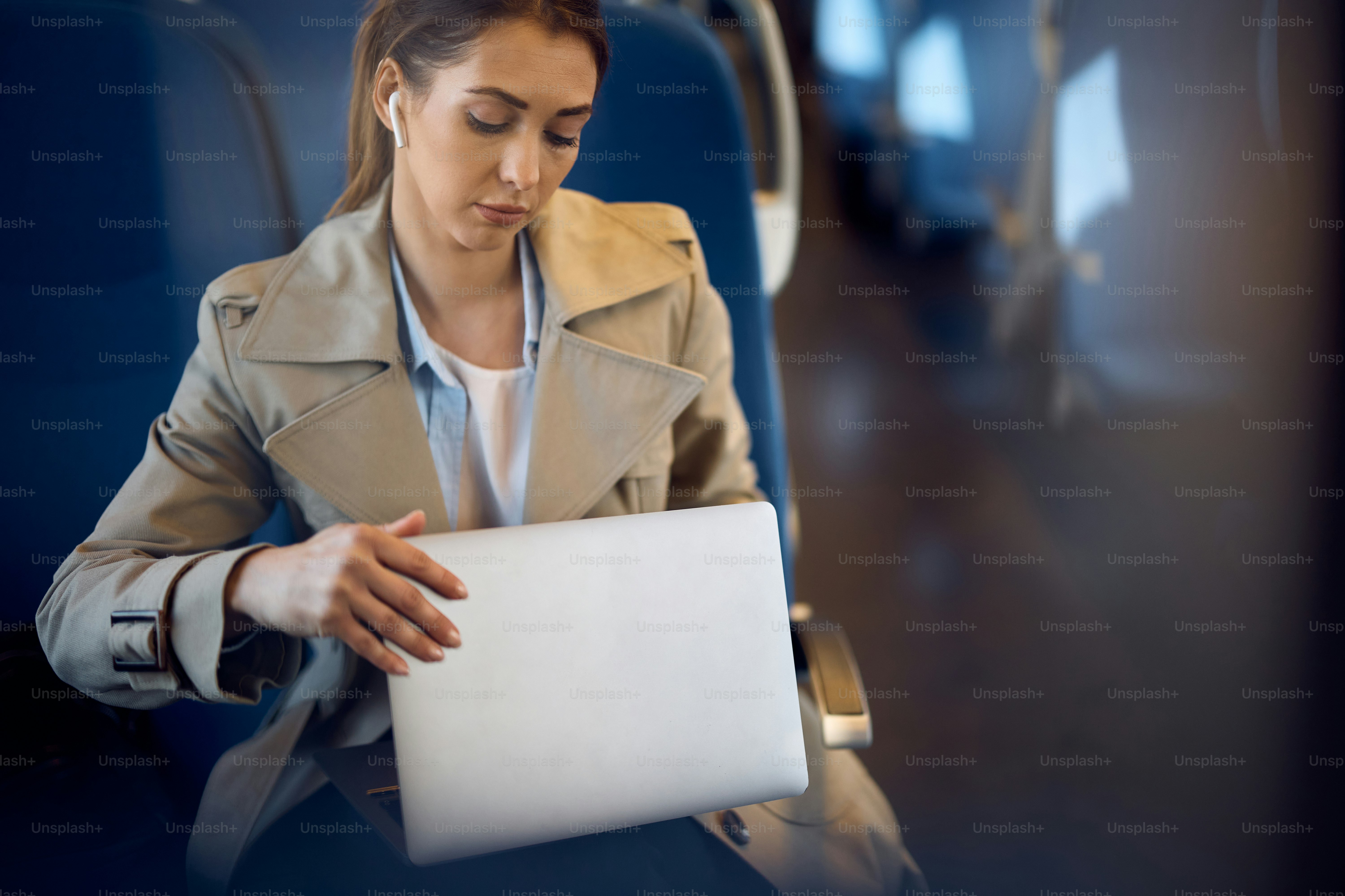 Young woman using her computer while commuting to work by train. photo ...