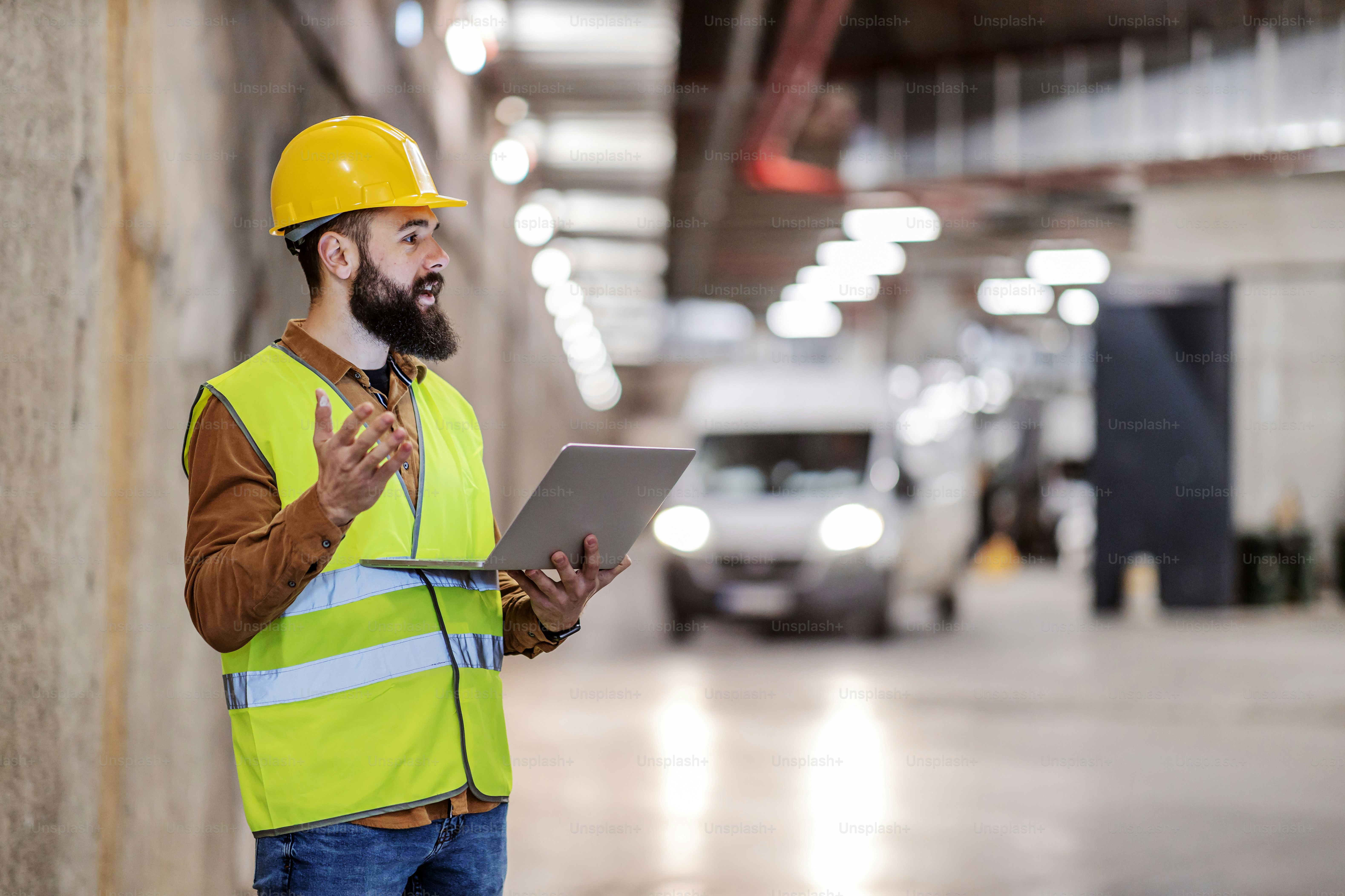 Young serious attractive contractor standing with laptop in hands and ...