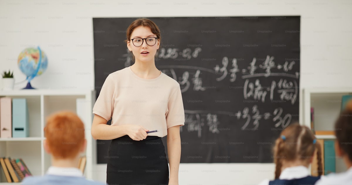 안경을 쓴 젊은 여자가 학교에서 교사로 일하고 학교 아이들을 가르치고 있다 사진 Unsplash의 교수 이미지