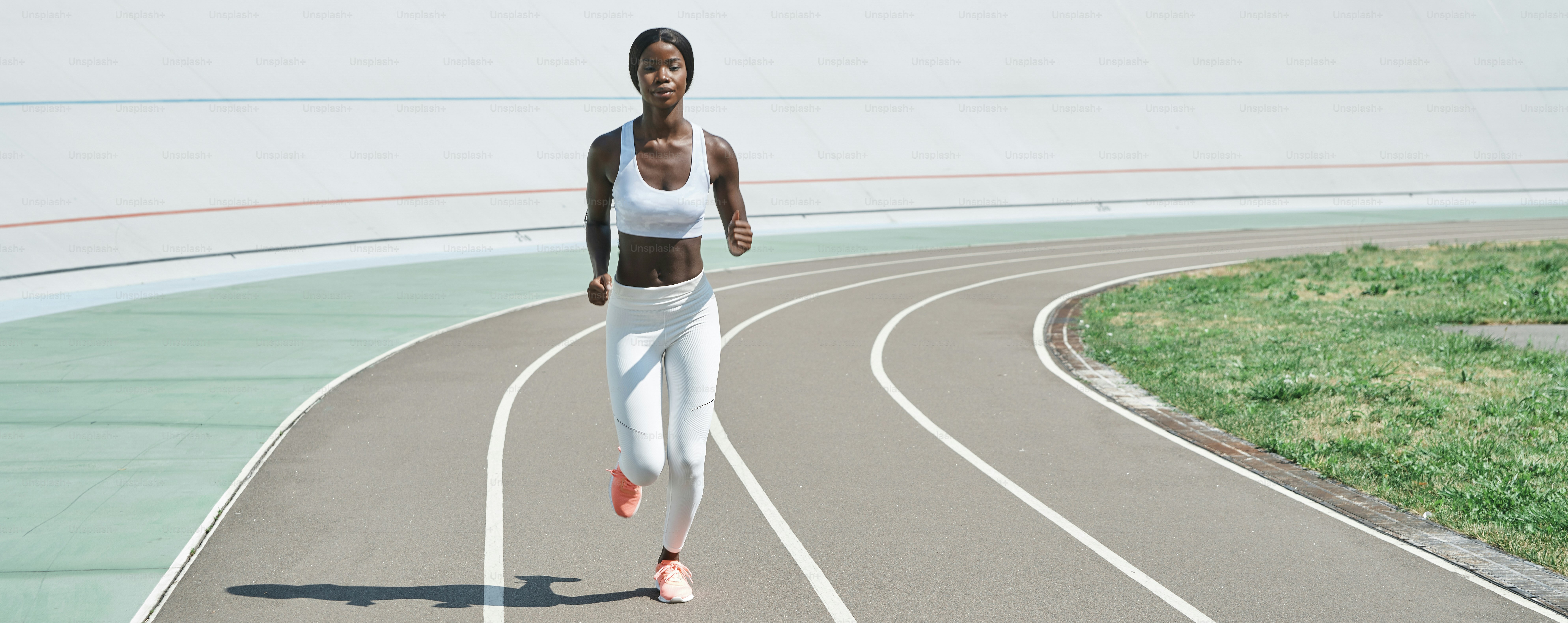 Full length of beautiful young African woman in sports clothing running ...