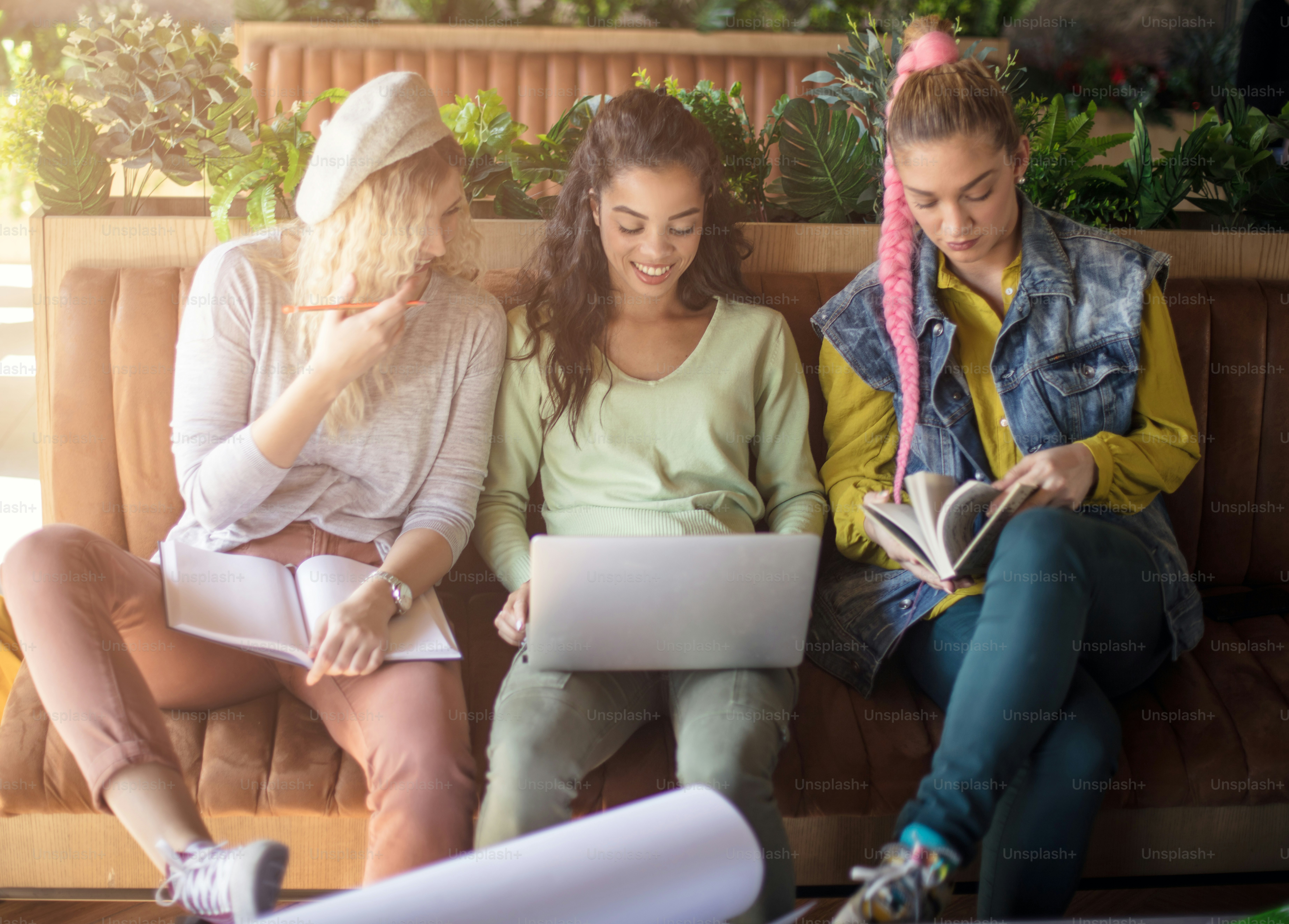 Finding the right apps that'll assist in their studies. Three students at cafe learning. photo ...