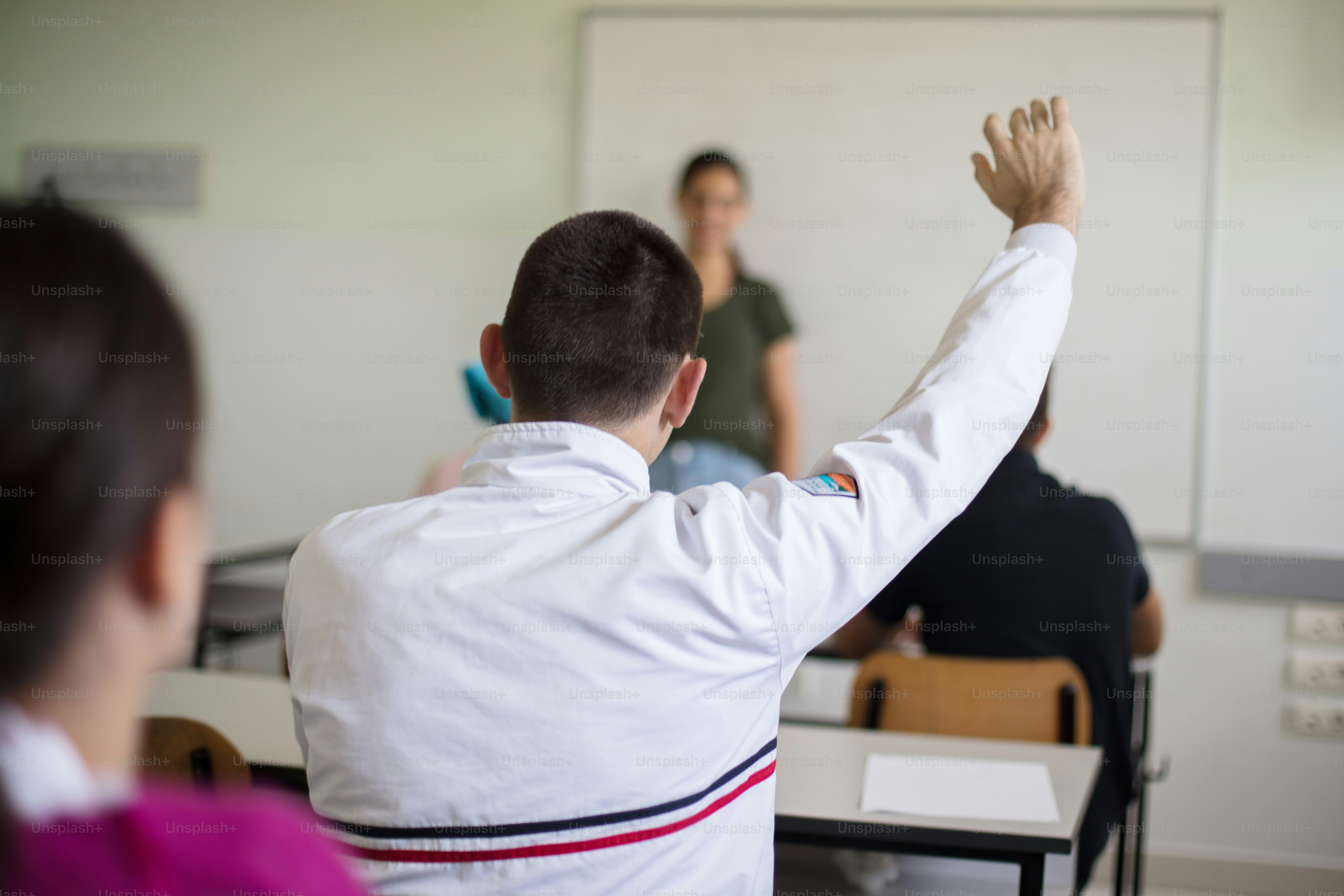 Smart students. Back view of elementary students raising their arms on ...