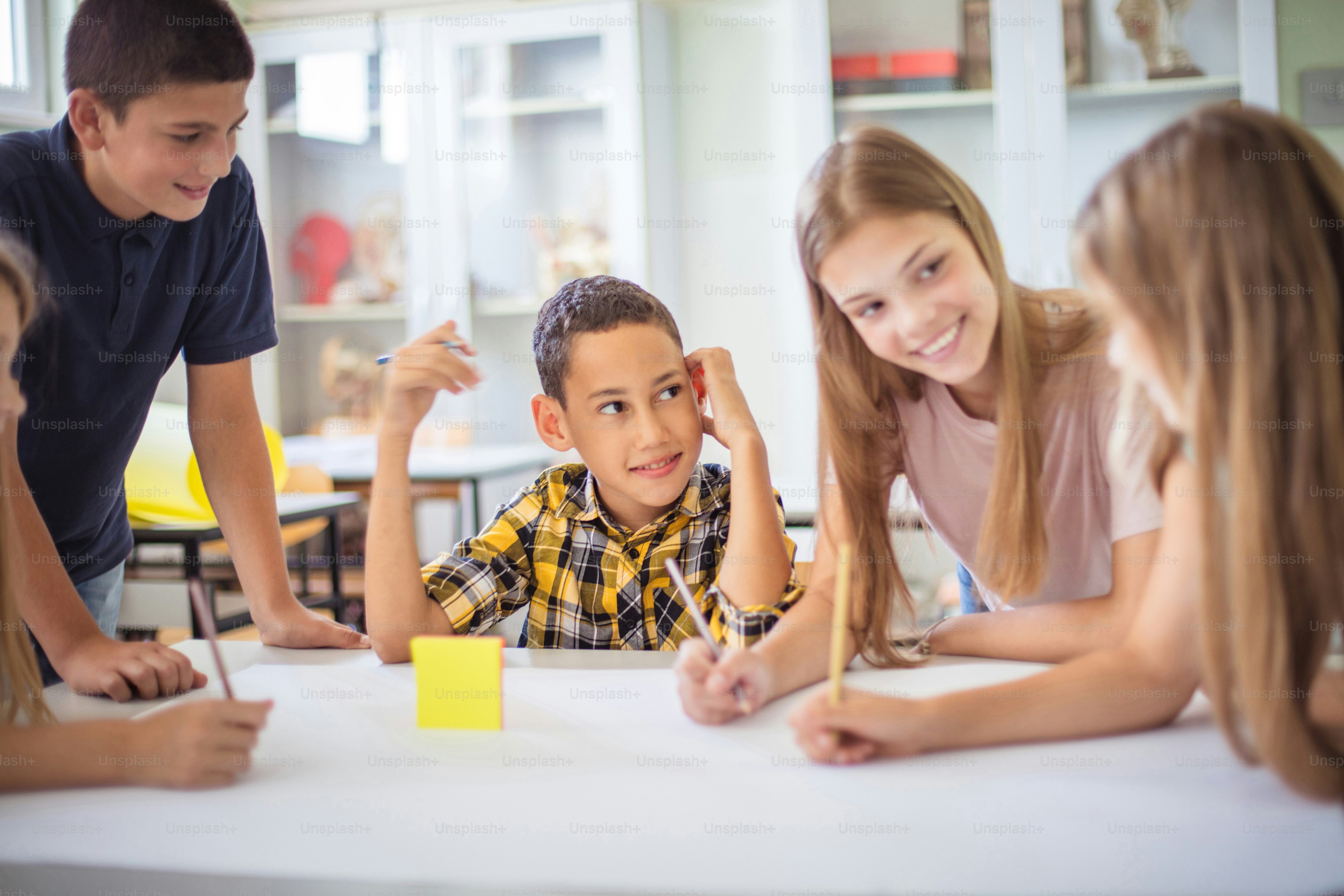 Great teamwork. Teenagers students sitting in the classroom and talking ...