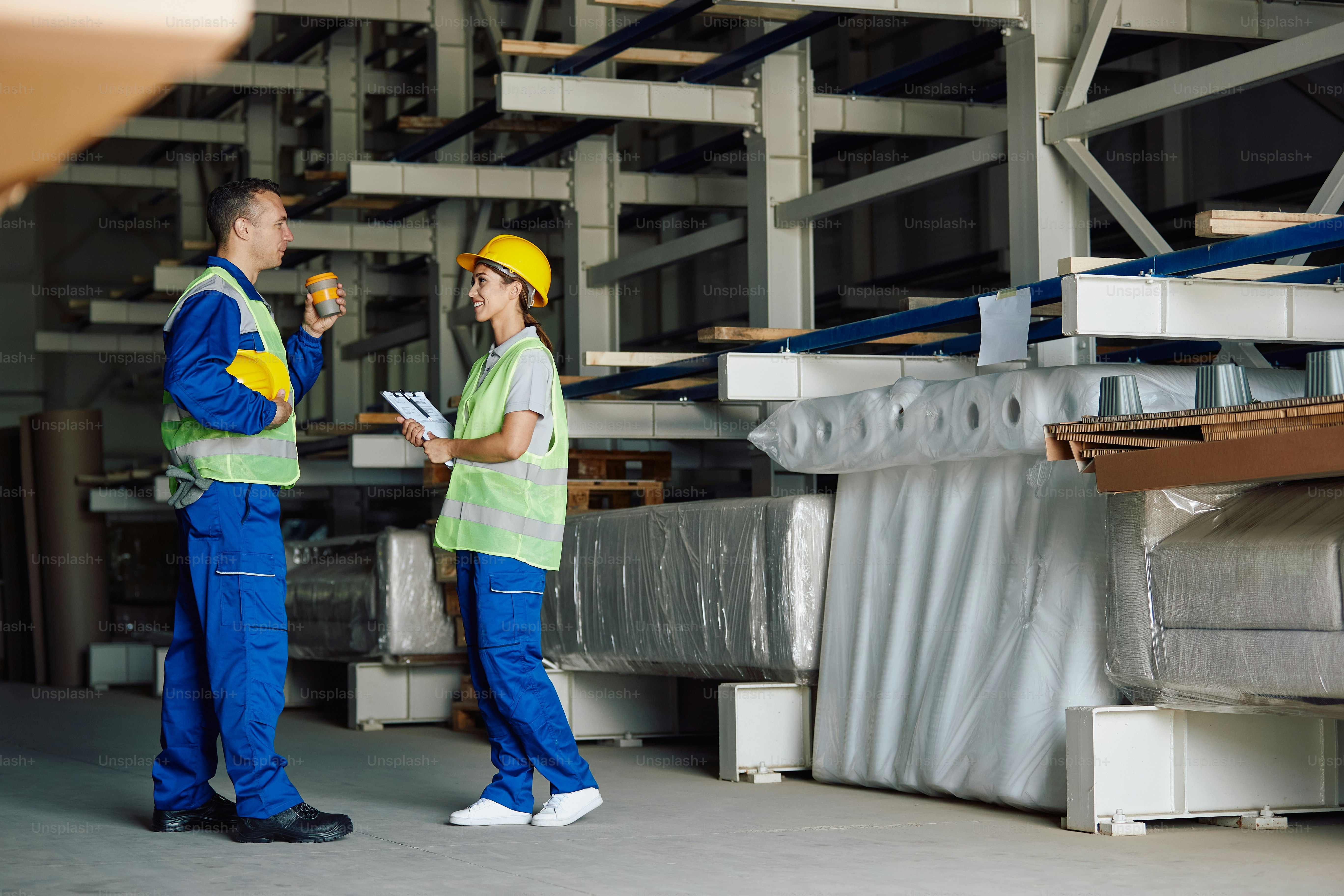 Happy manual worker drinking coffee and talking to female coworker in a ...