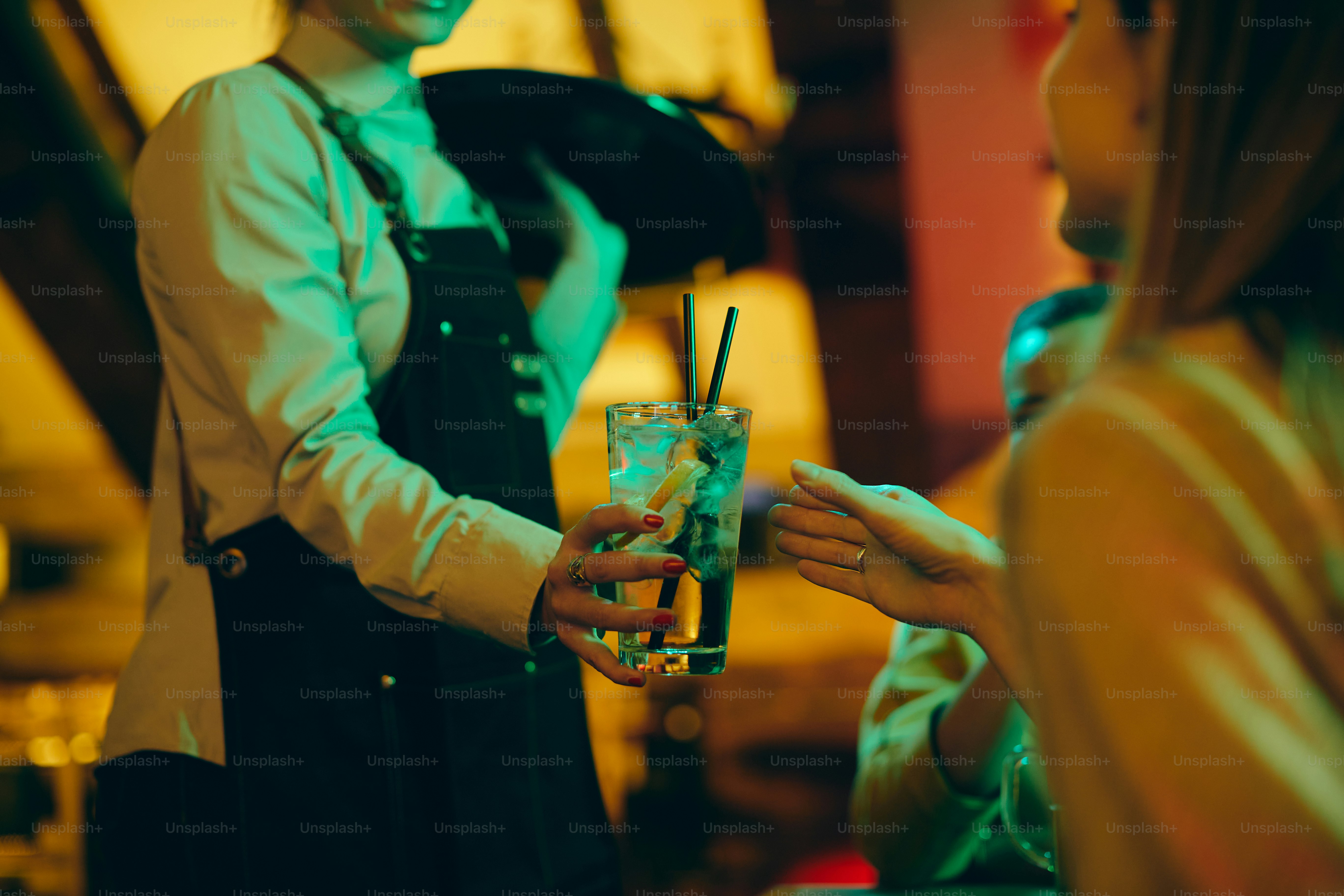 Gros plan d’une serveuse servant des boissons à des clients dans un pub ...