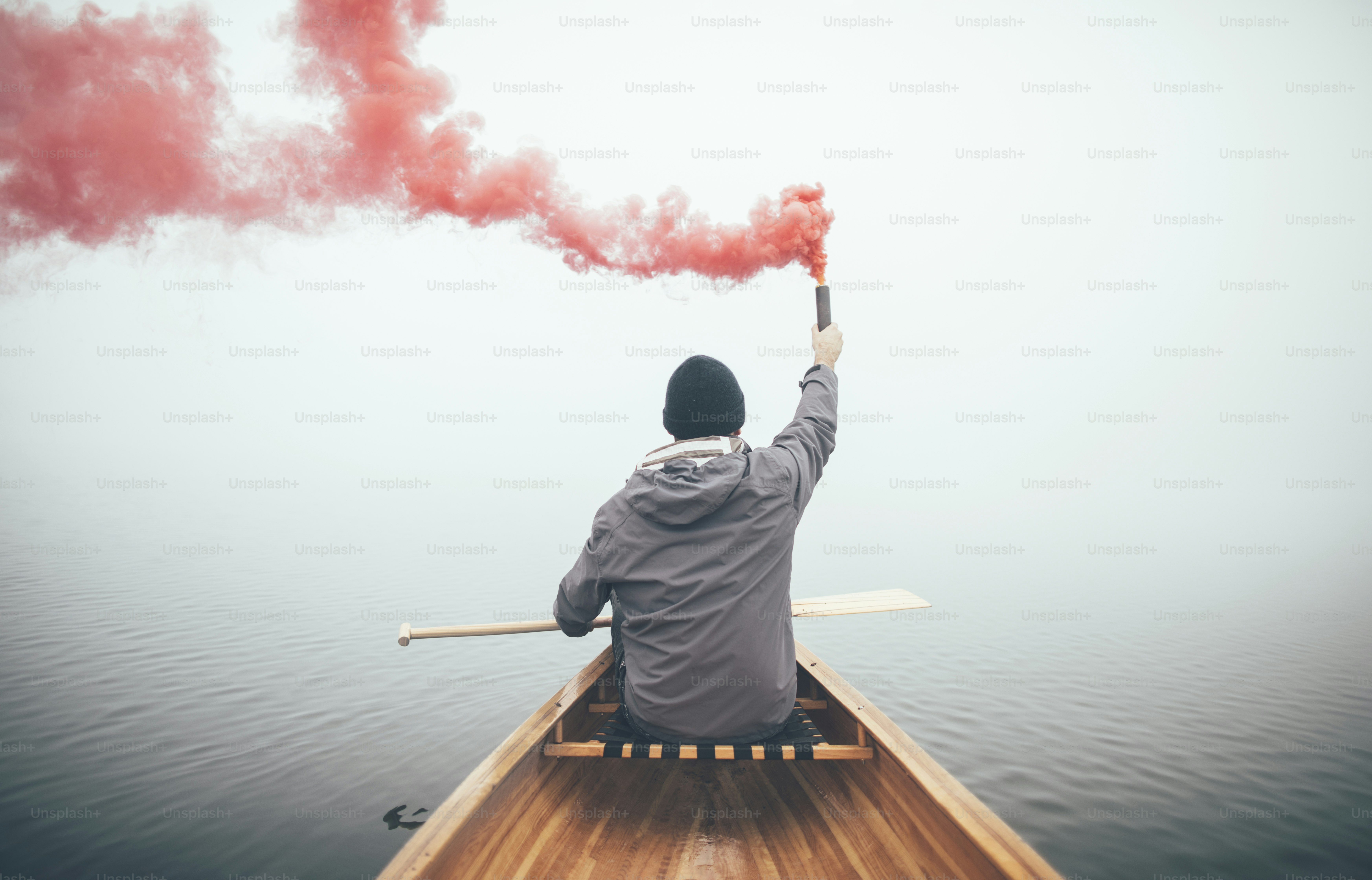 Rear view of canoeist using smoke bomb to signal his position in the ...