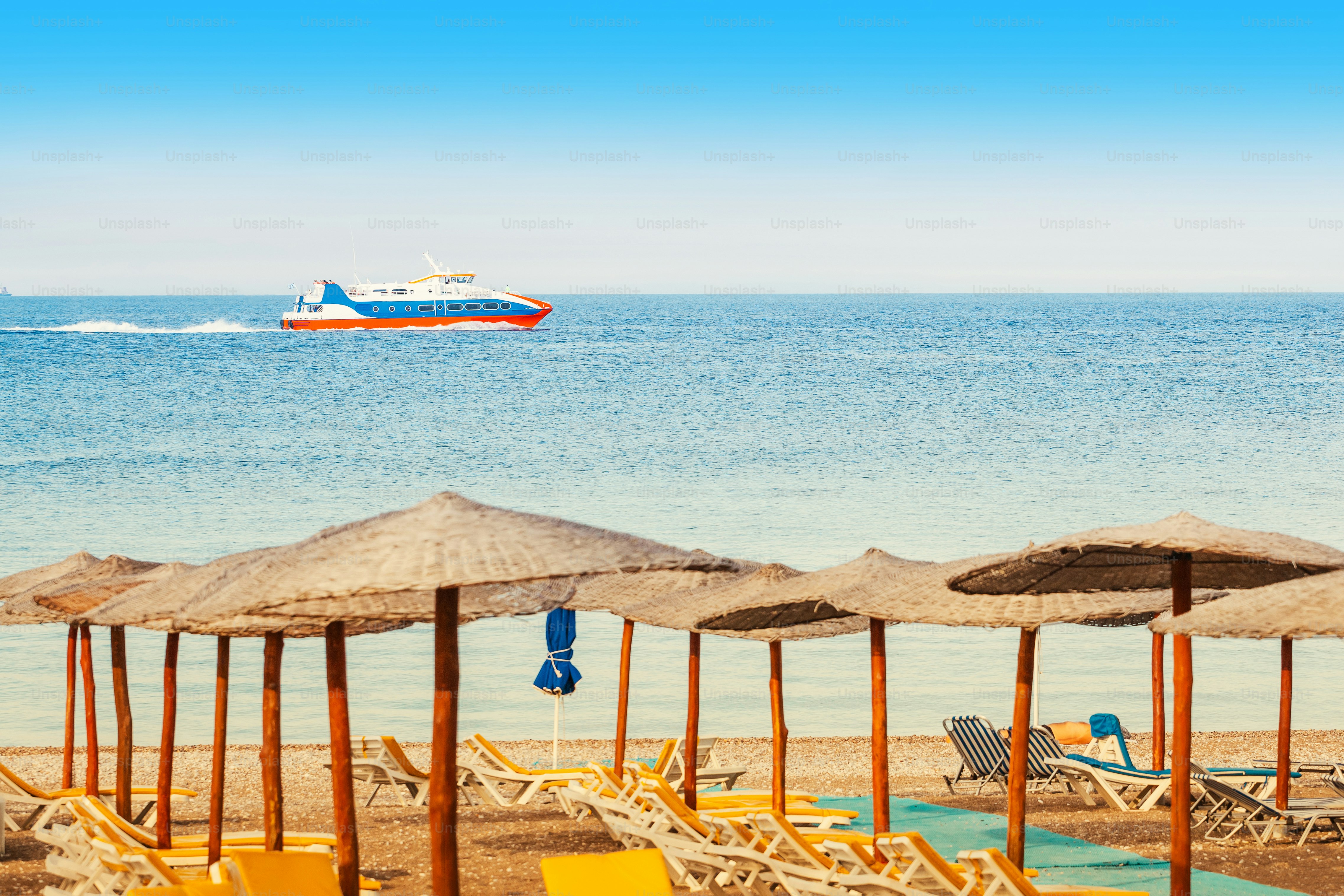 Tropical beach with sunbeds and ferry ship in distance photo – The ...