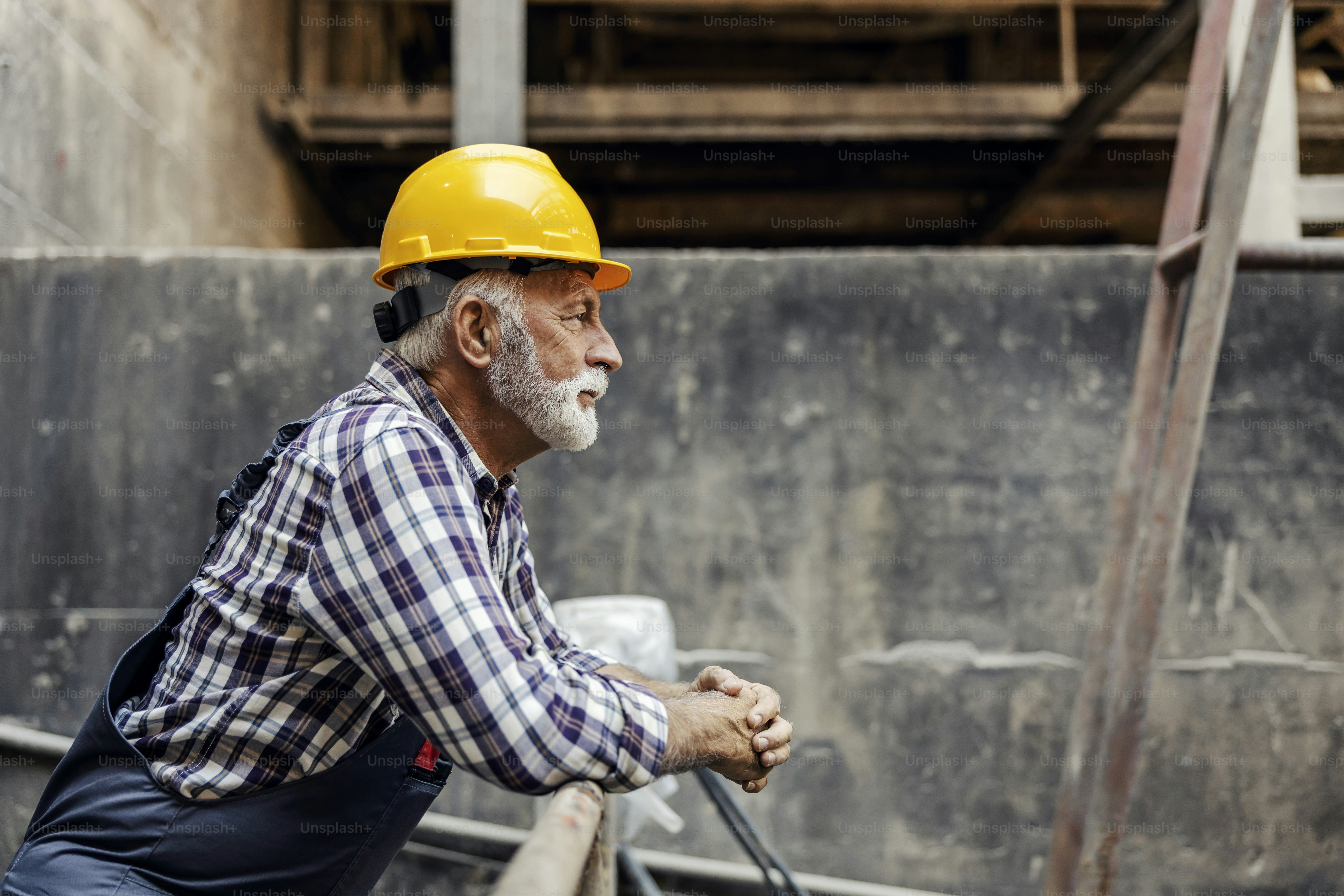 A senior factory adviser in overalls, with a helmet on his head ...