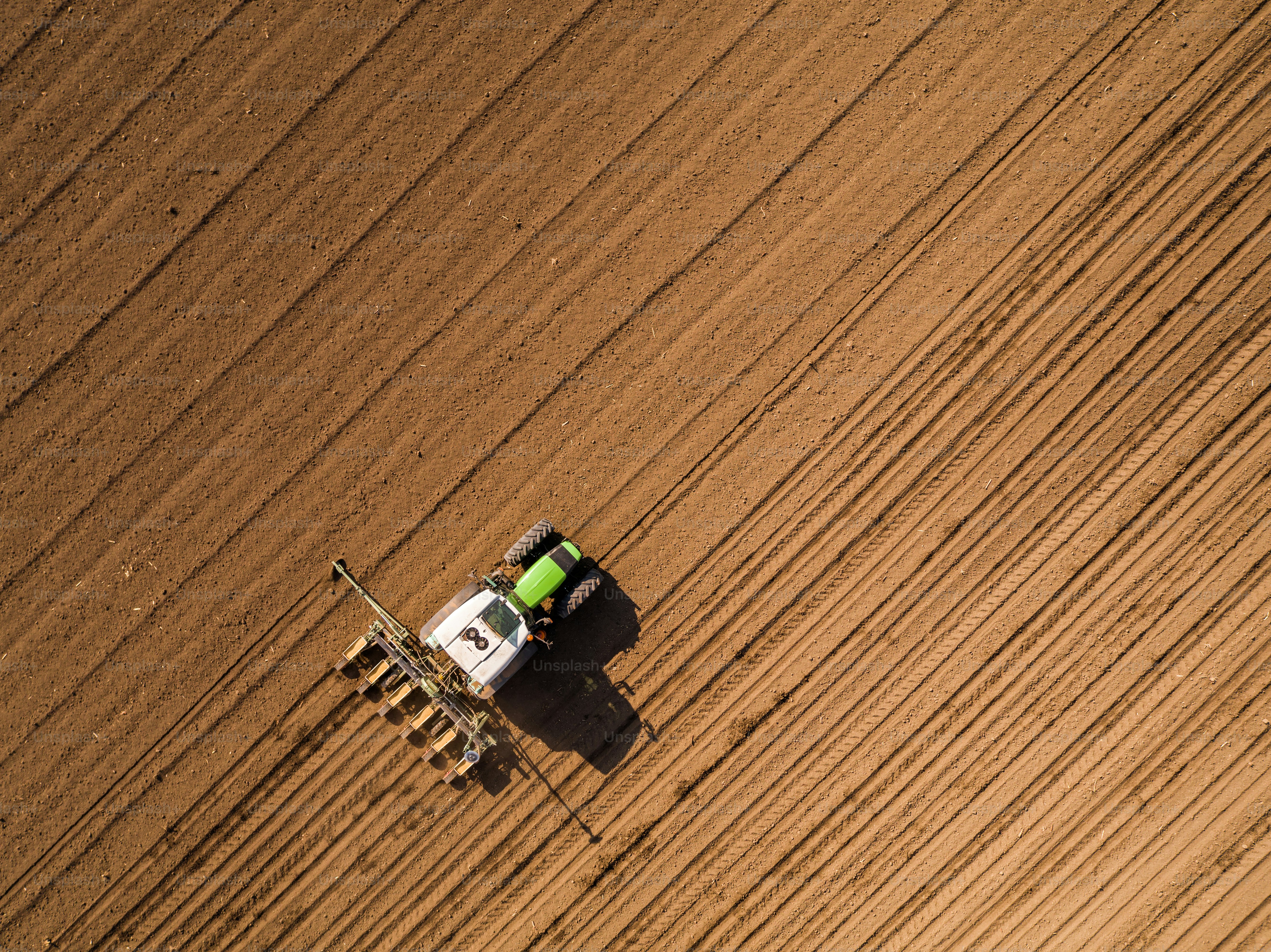 Aerial shot of a farmer seeding, sowing crops at field. Sowing is the ...