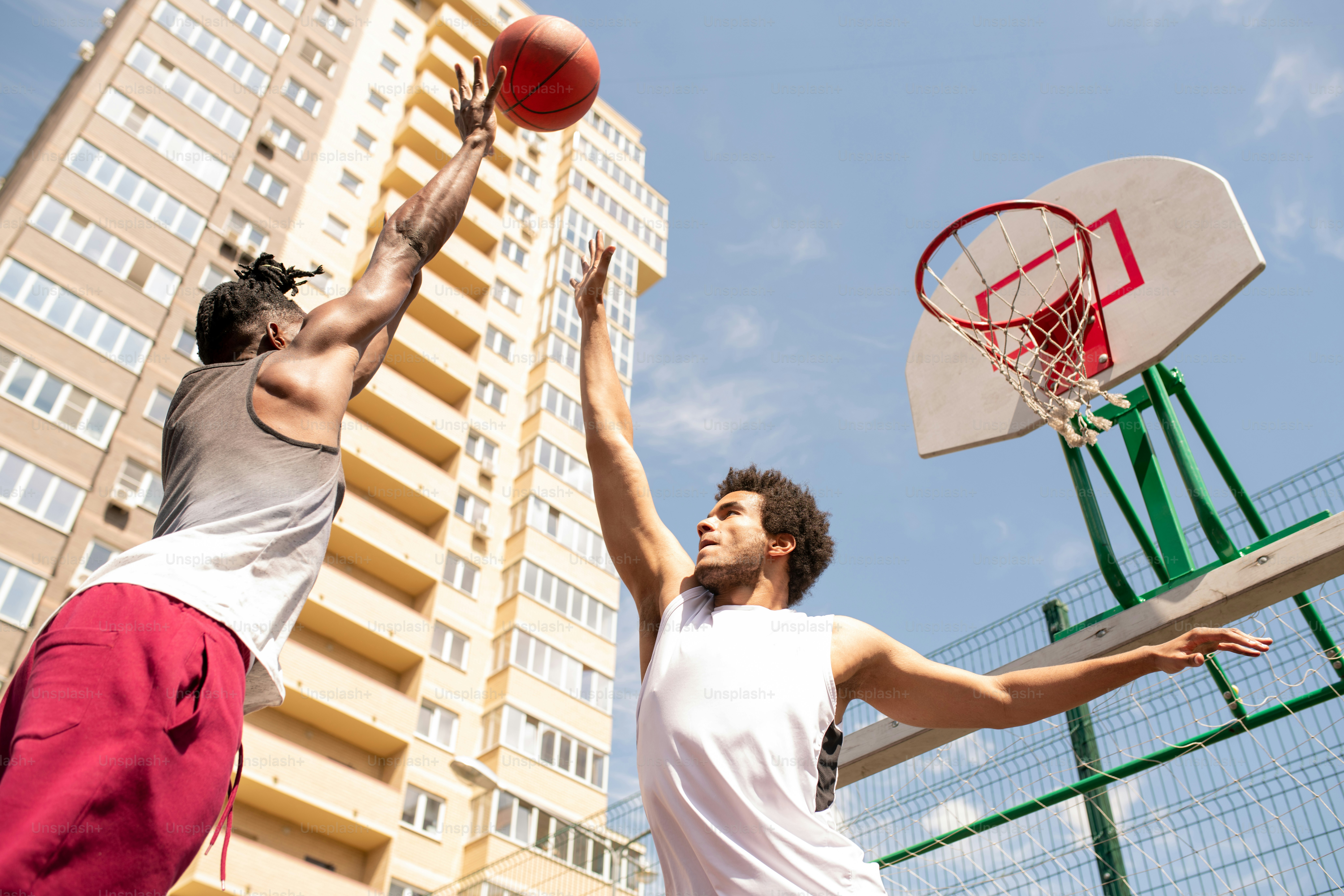 One of young intercultural basketball players attacking the ball while ...