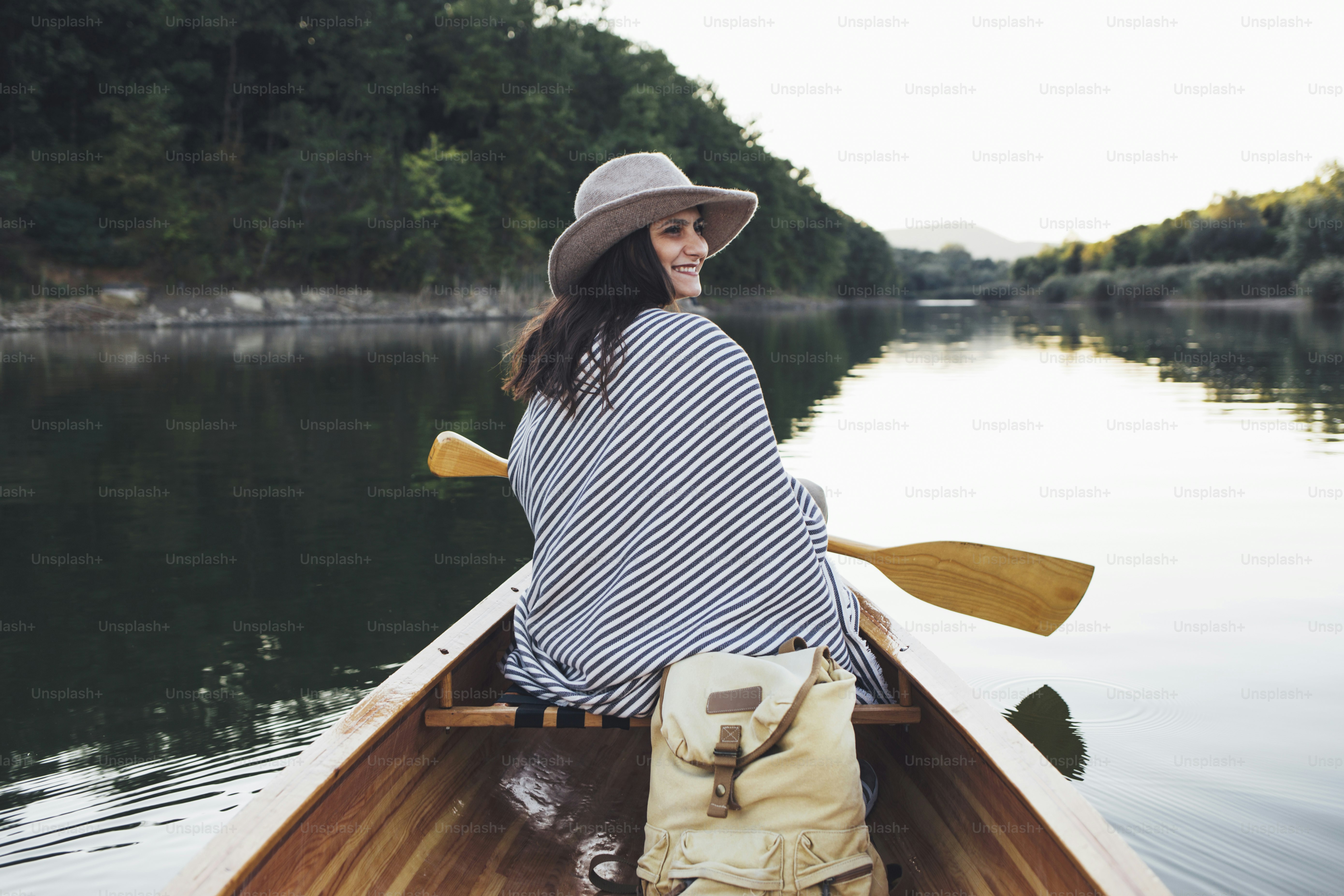 Smiling young woman paddling the canoe on the sunset lake. photo ...