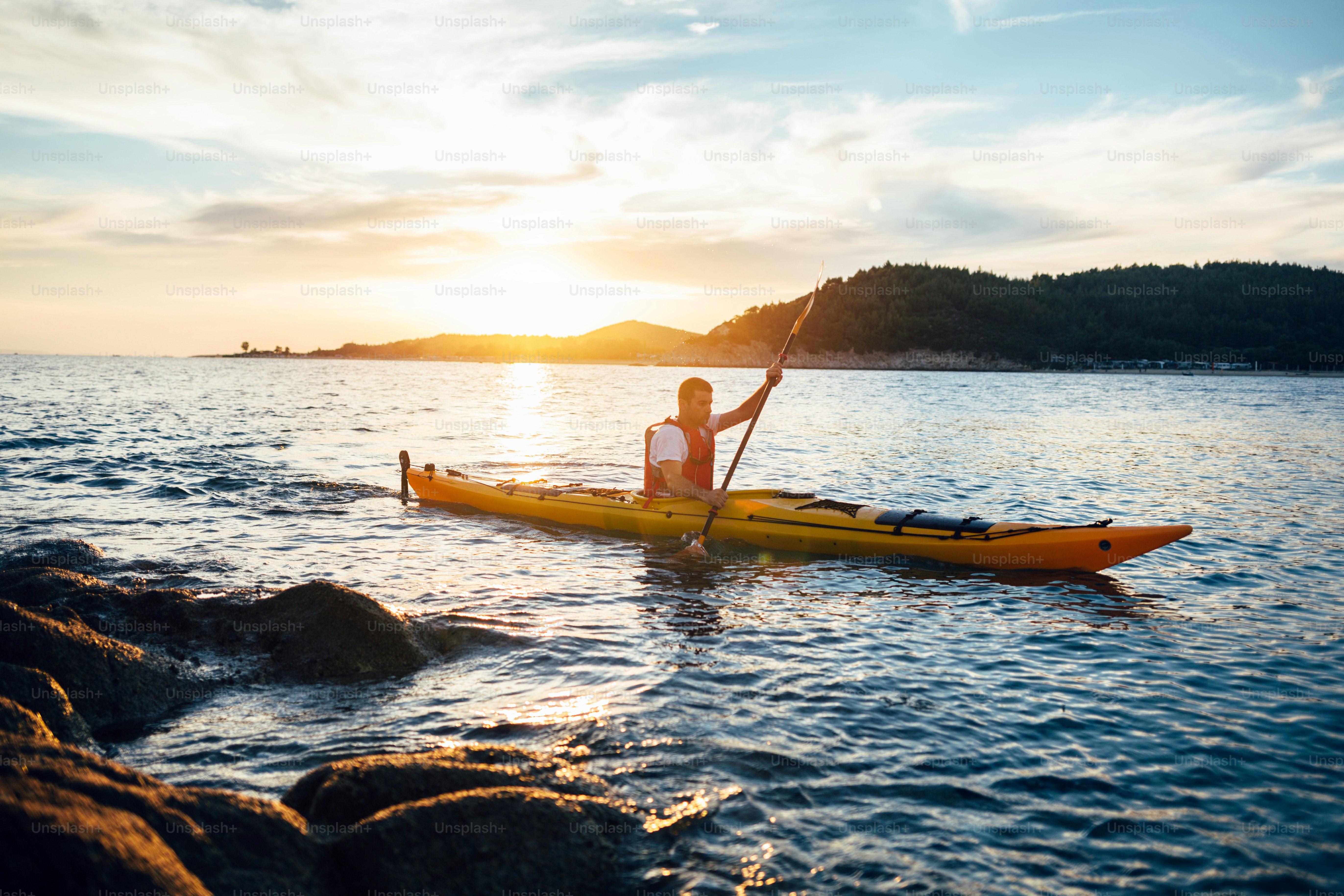 Hombre kayakista remando en el kayak en el mar al atardecer. foto ...