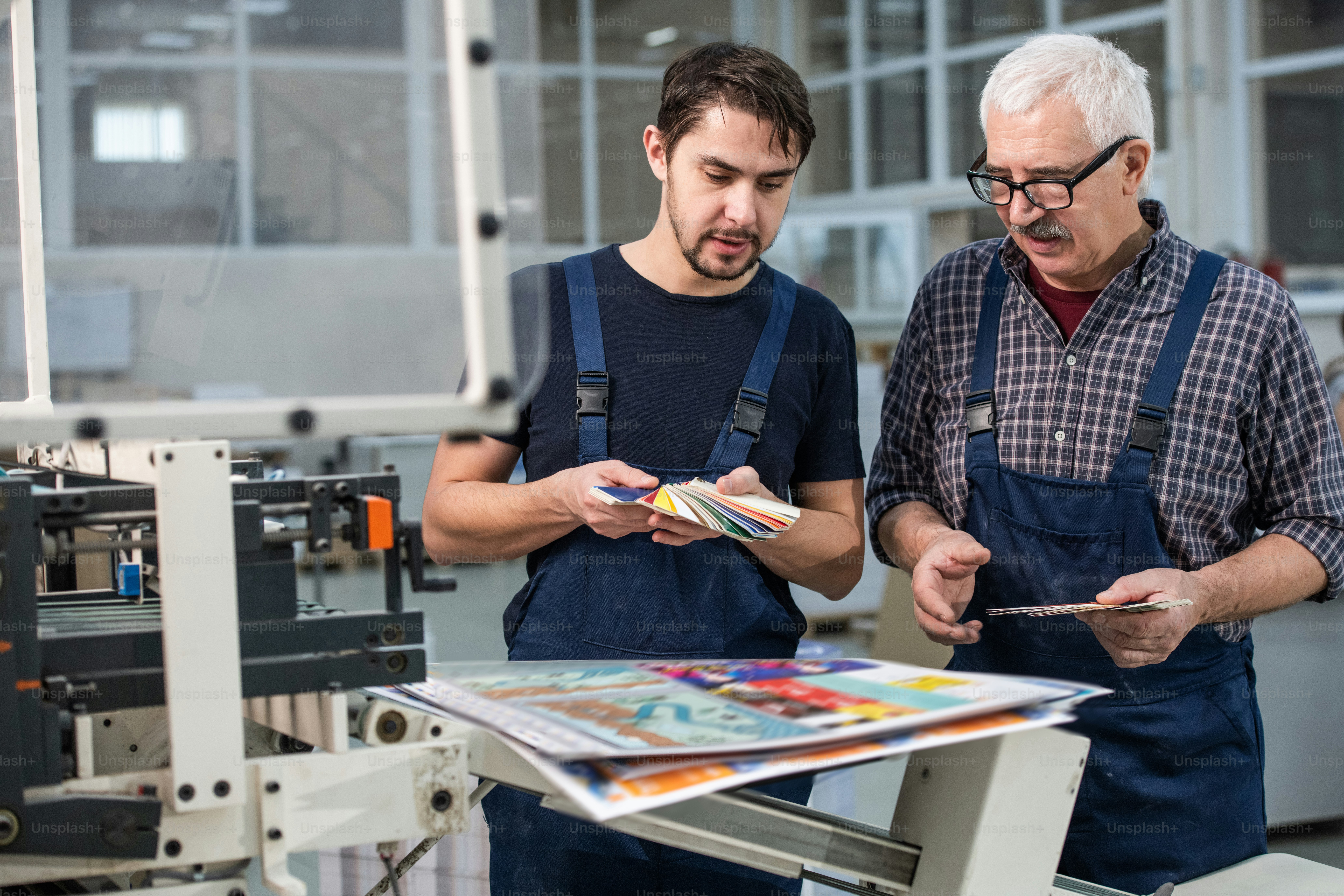 Busy printing plant workers standing at printed pages and choosing ...