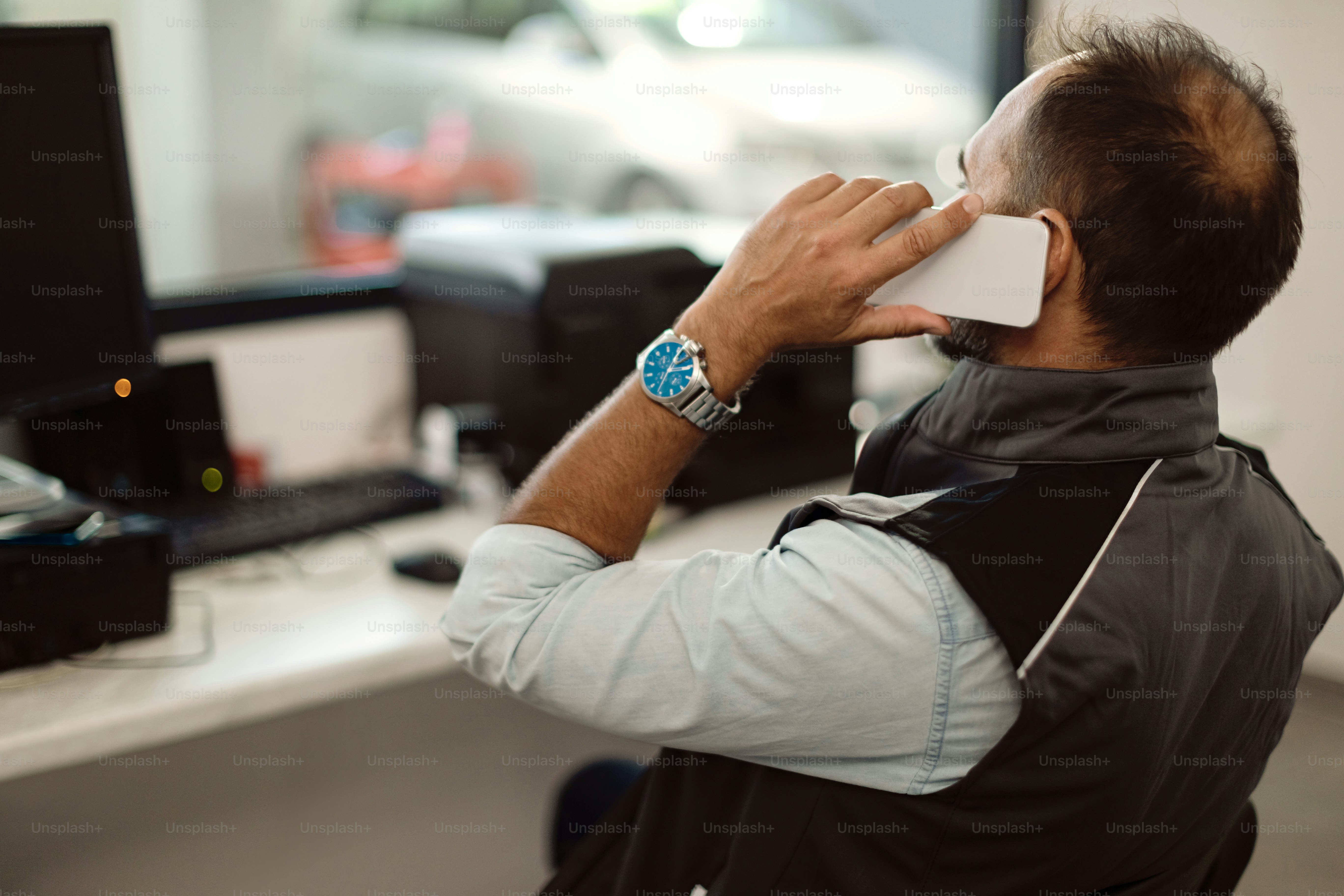 Auto repairman communicating over cell phone while sitting in the ...